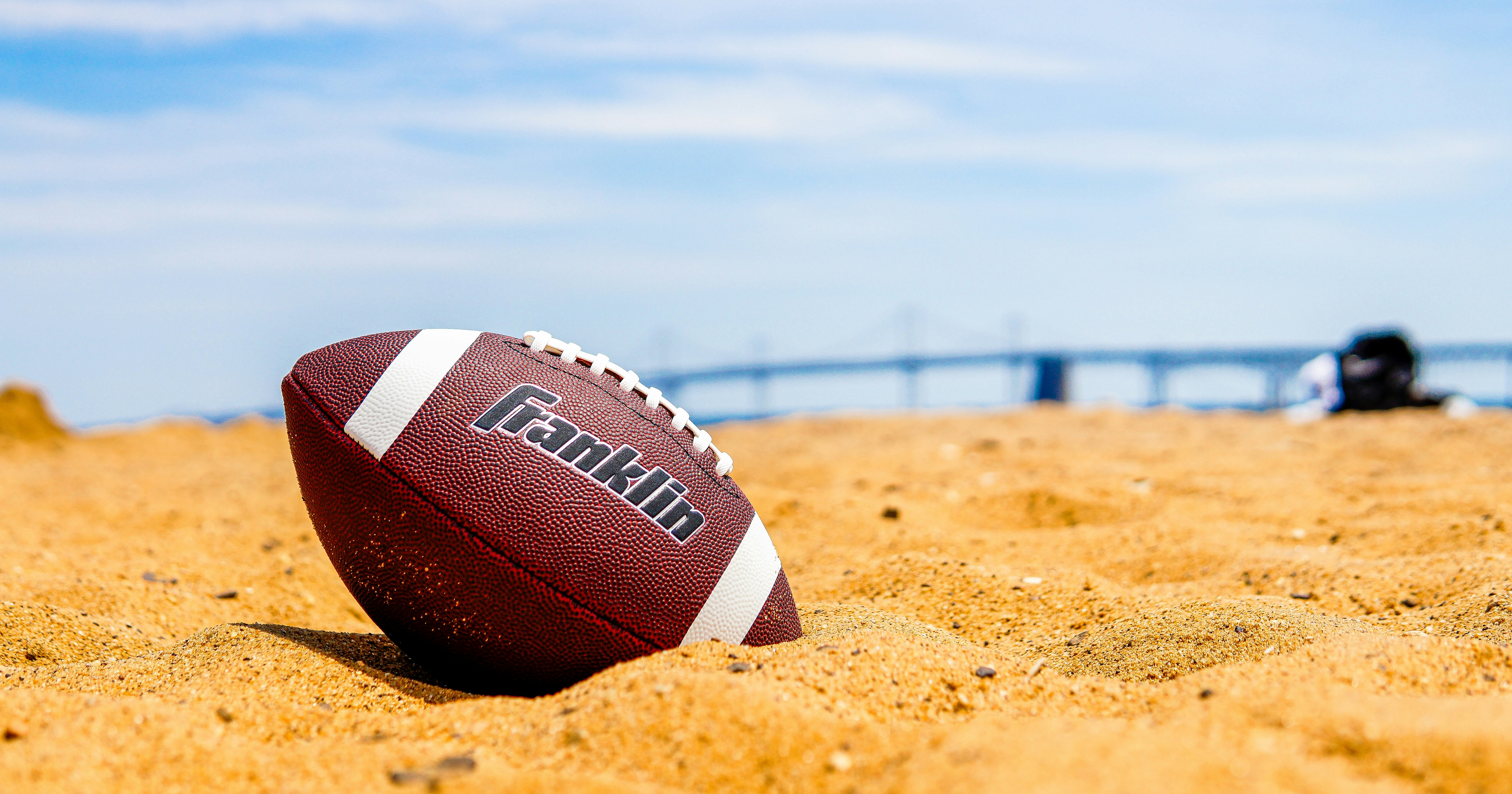 Frayed Grip: A Lone Football Resting in Sunny Sand