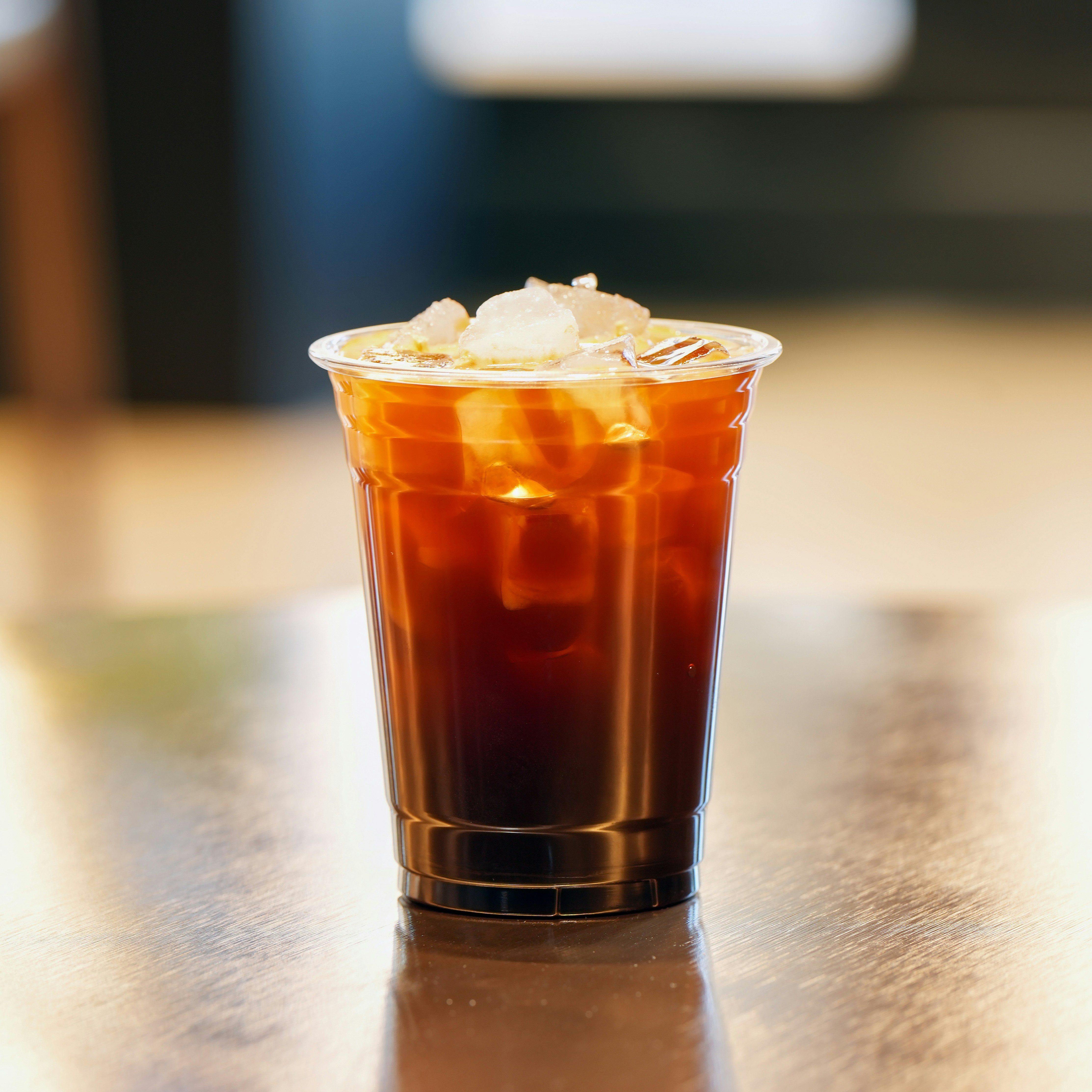 Amber Elixir in Focus: A Glass of Iced Coffee on a Sunny Counter