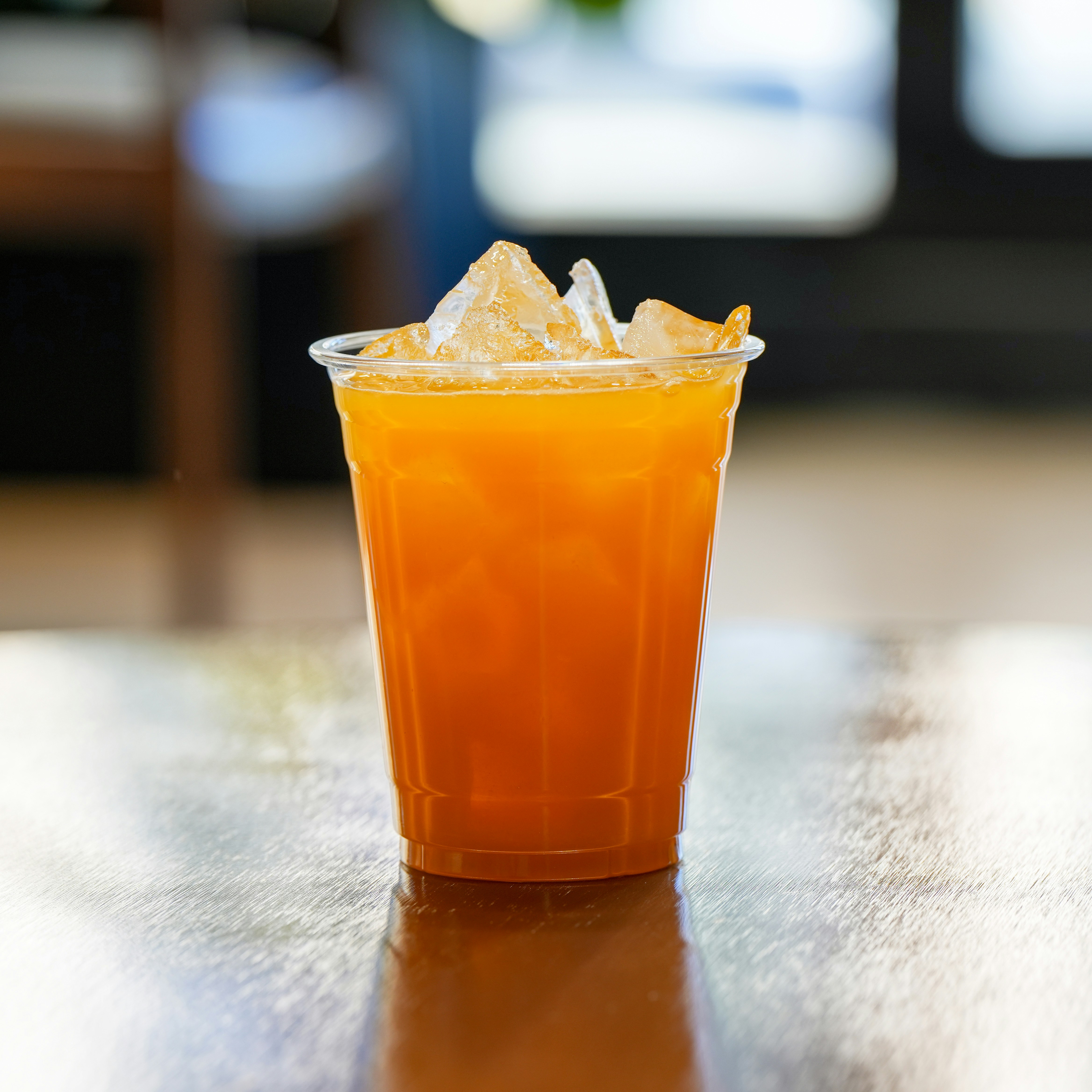 Iced orange beverage in a plastic cup.