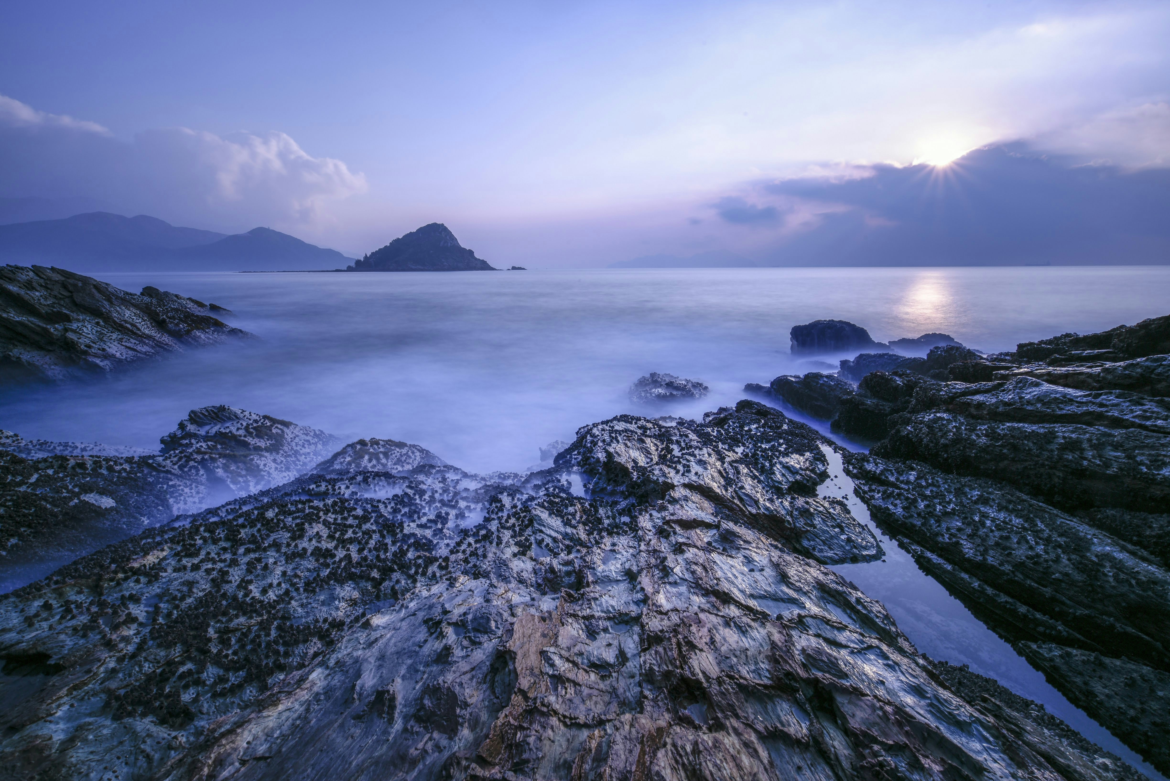 Rugged coastline at blue hour with distant islands and glassy sea