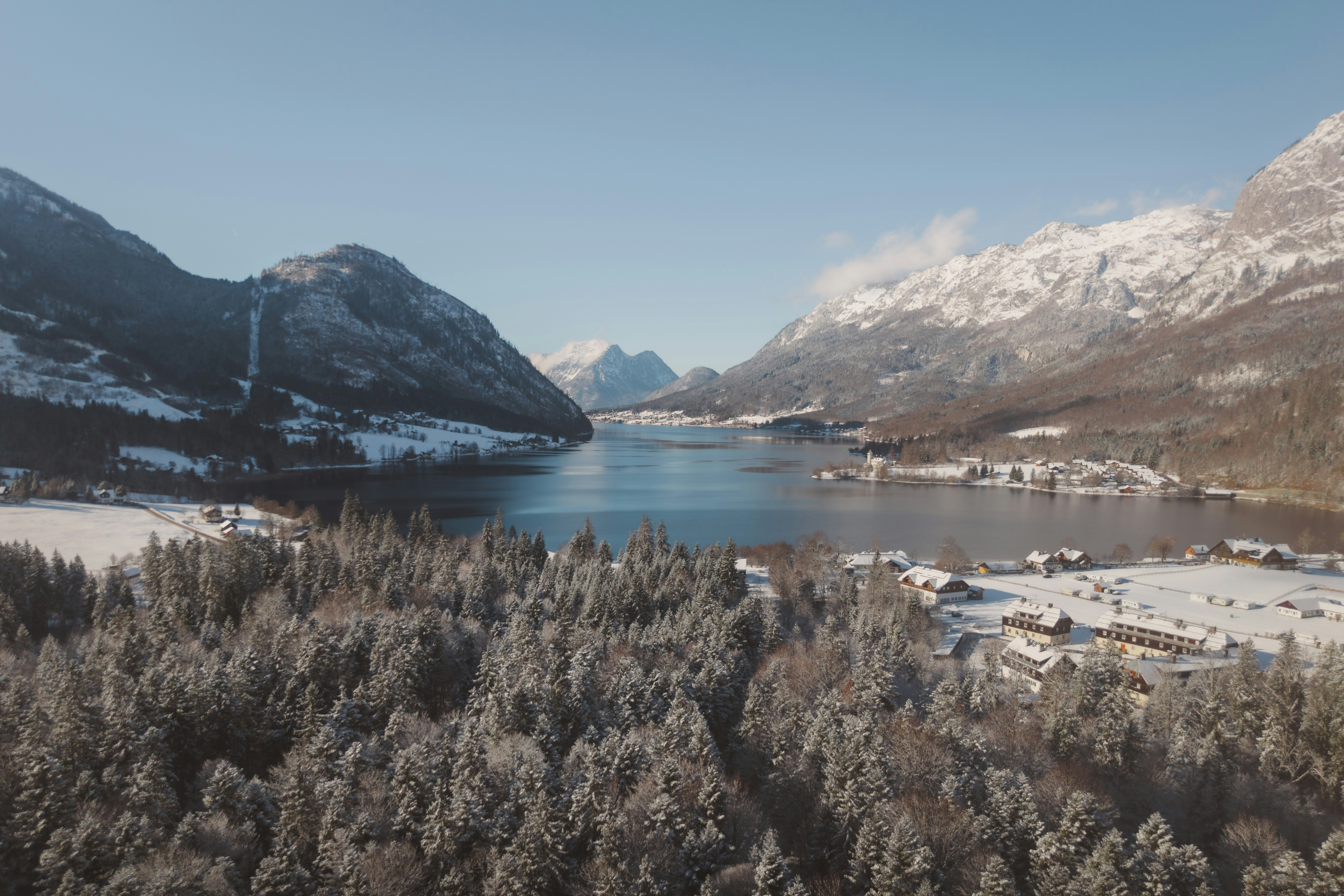 Snow-kissed valley and glacier-fed lake under clear alpine sky