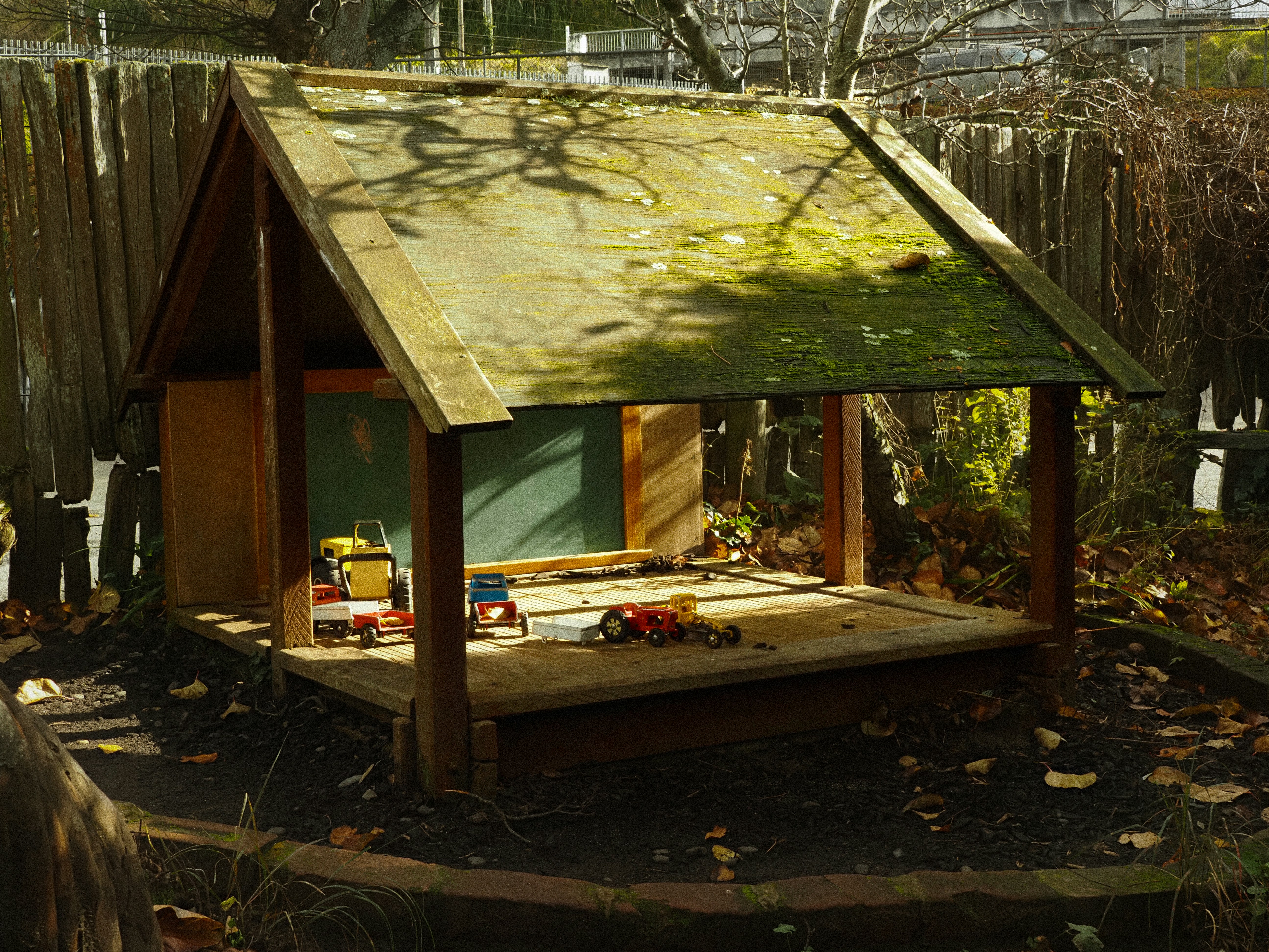 A small wooden playhouse with toy cars inside, photographed in New Zealand in warm natural light.