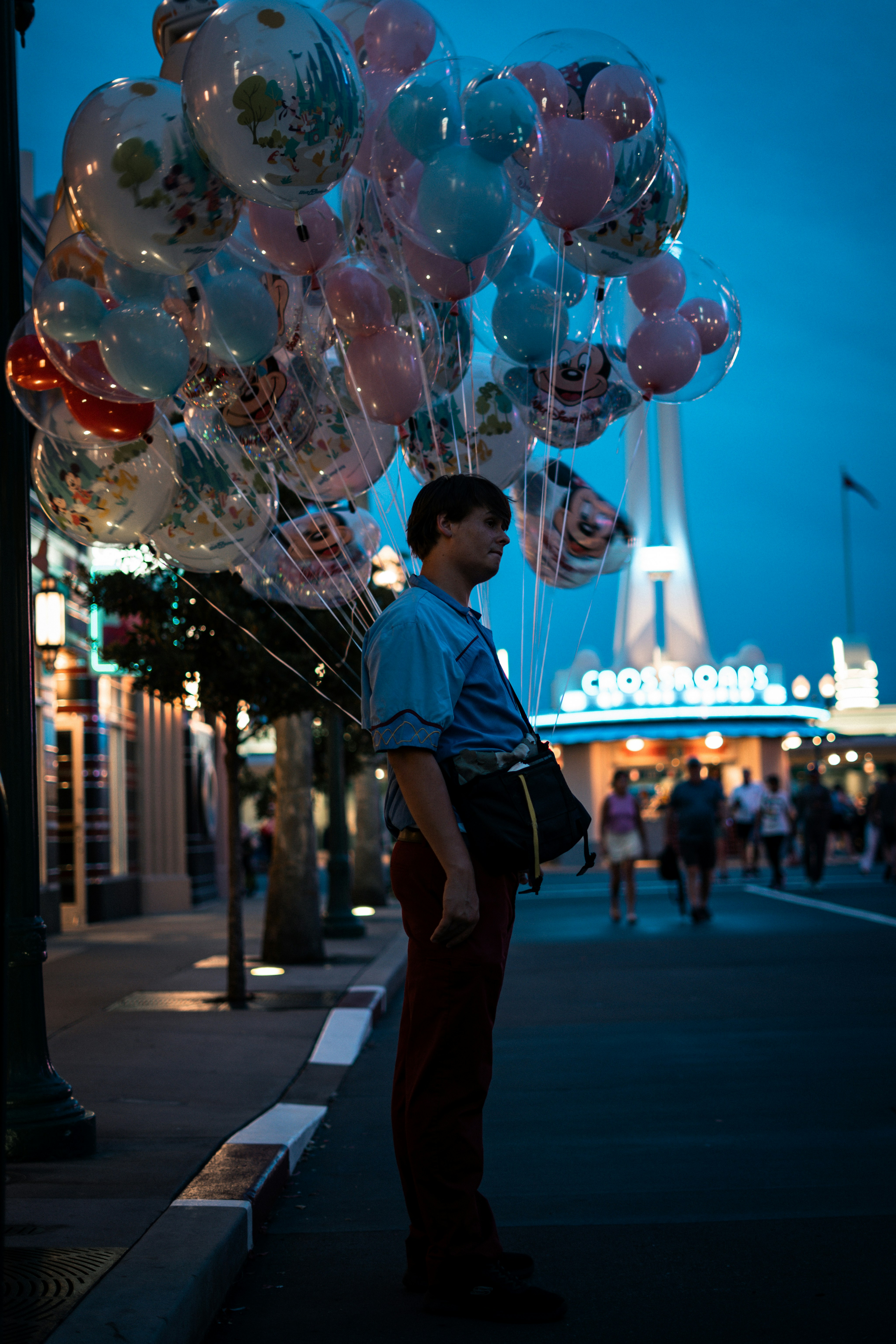 Balloon vendor in twilight with neon backdrop