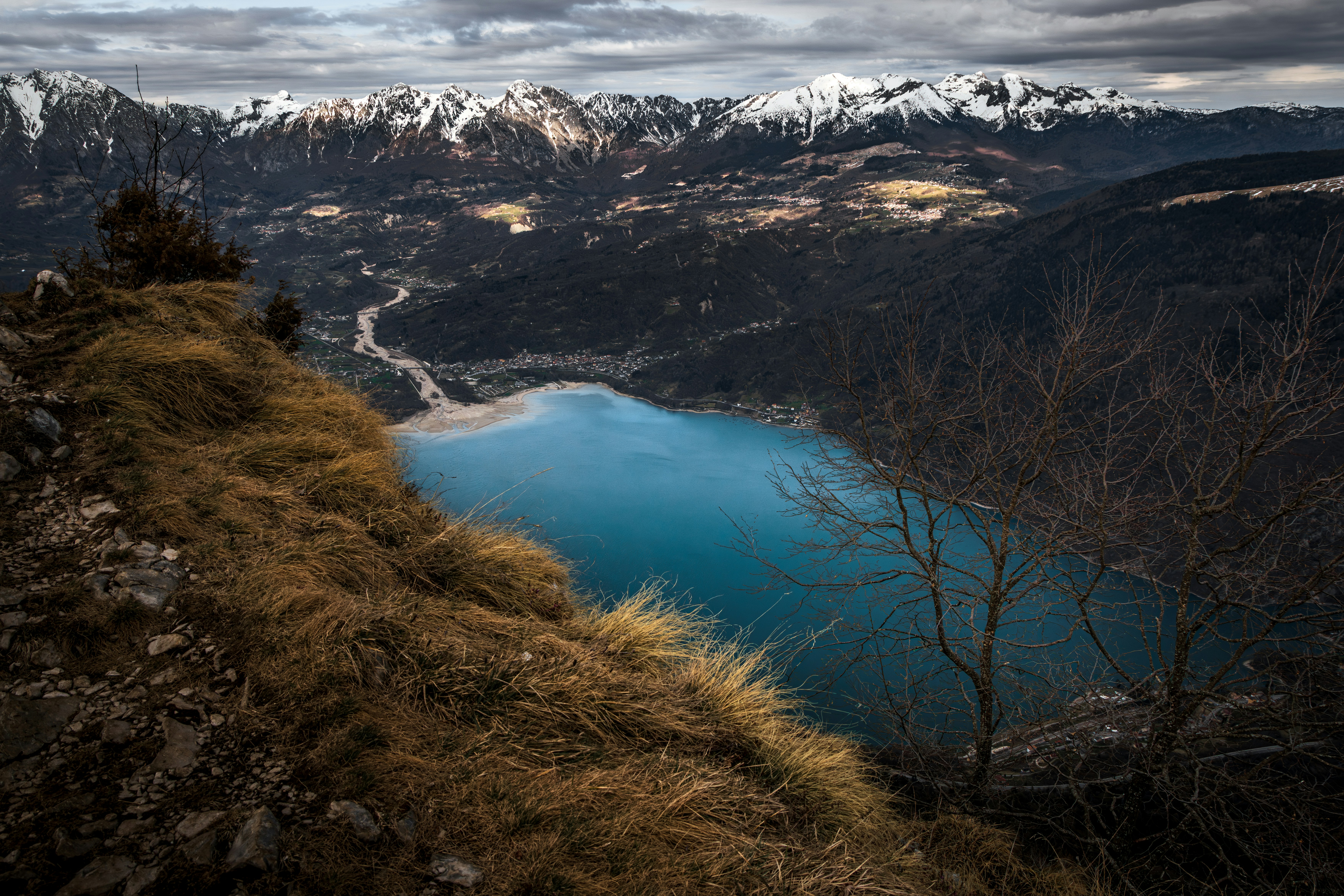 A blue lake in a valley surrounded by snowy mountains.