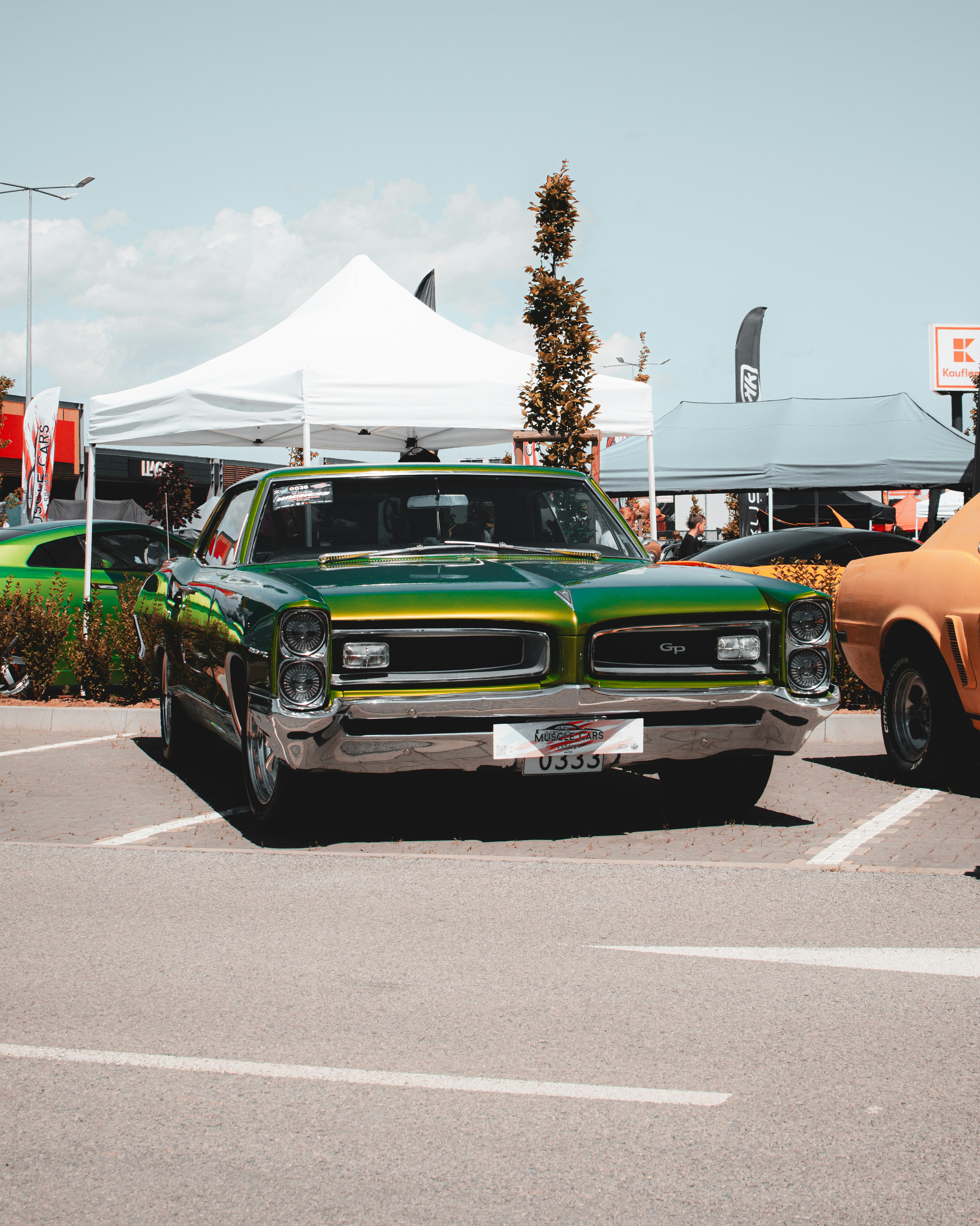 Green Classic: A Bright Buick Stands Center in a Sunlit Car Show