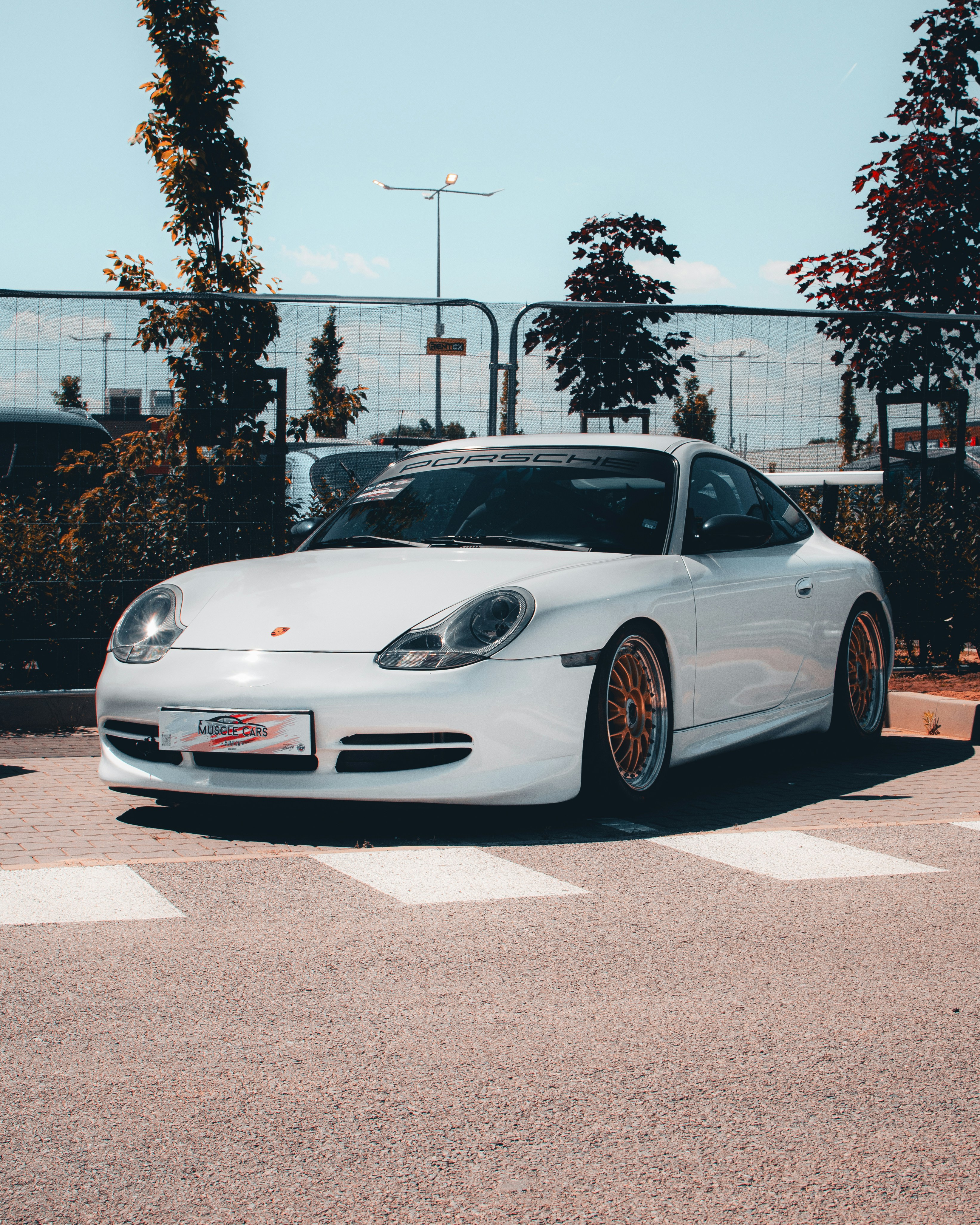 White Porsche Stance: Low-slung coupe under bright afternoon sun