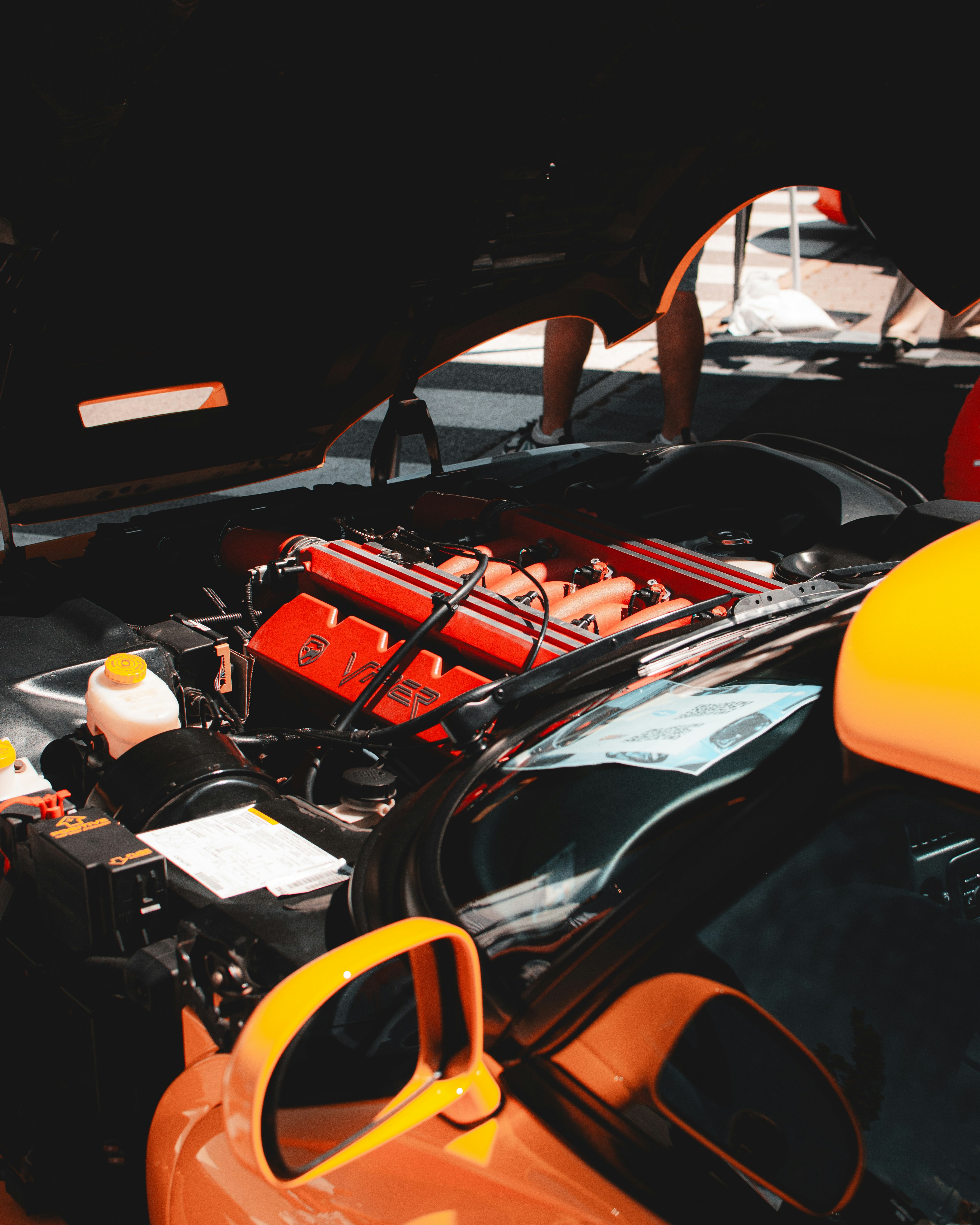 Vivid orange engine bay under open hood of a sports car