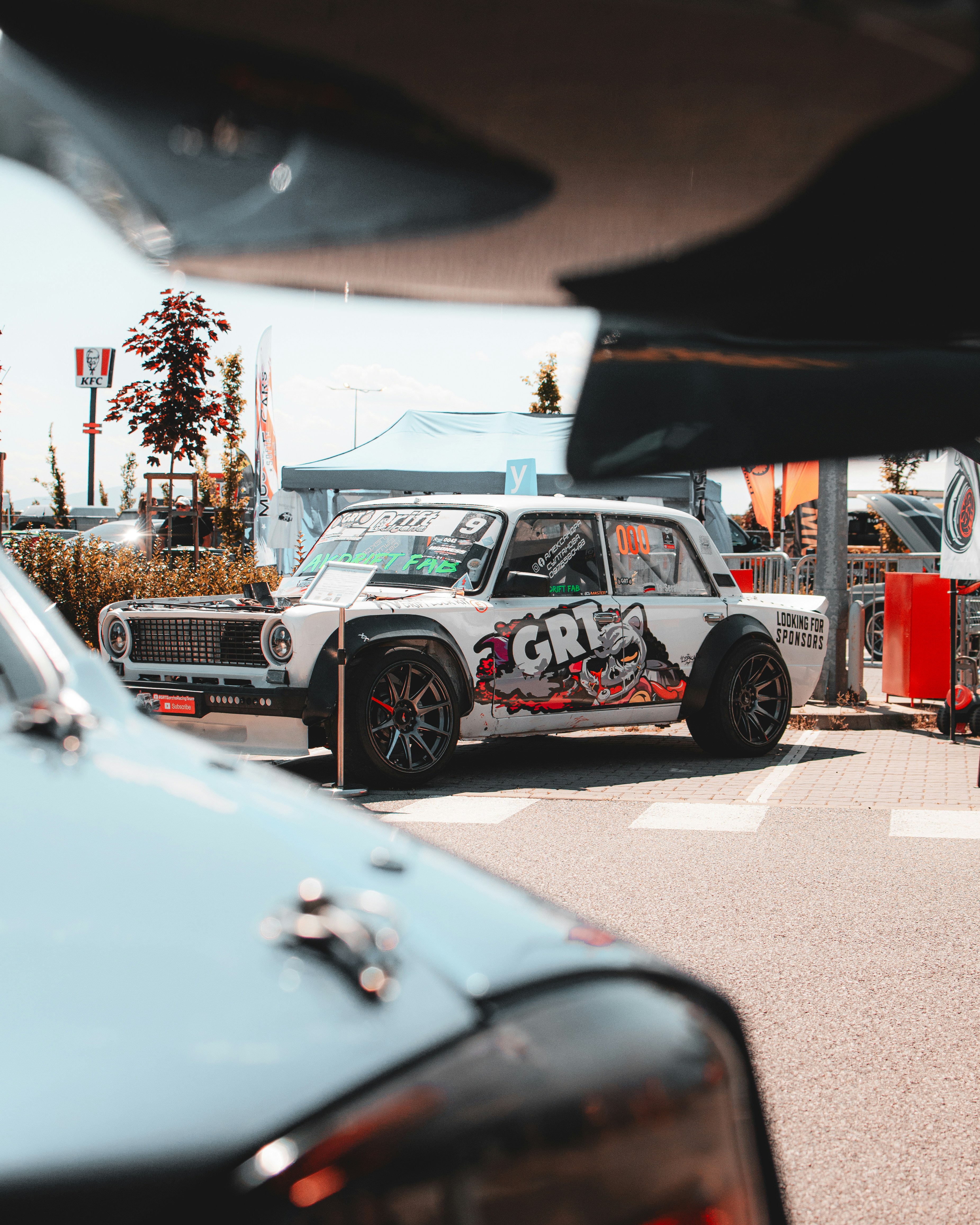 Graffiti-rimmed Drift: A Gleaming Car at a Car Show