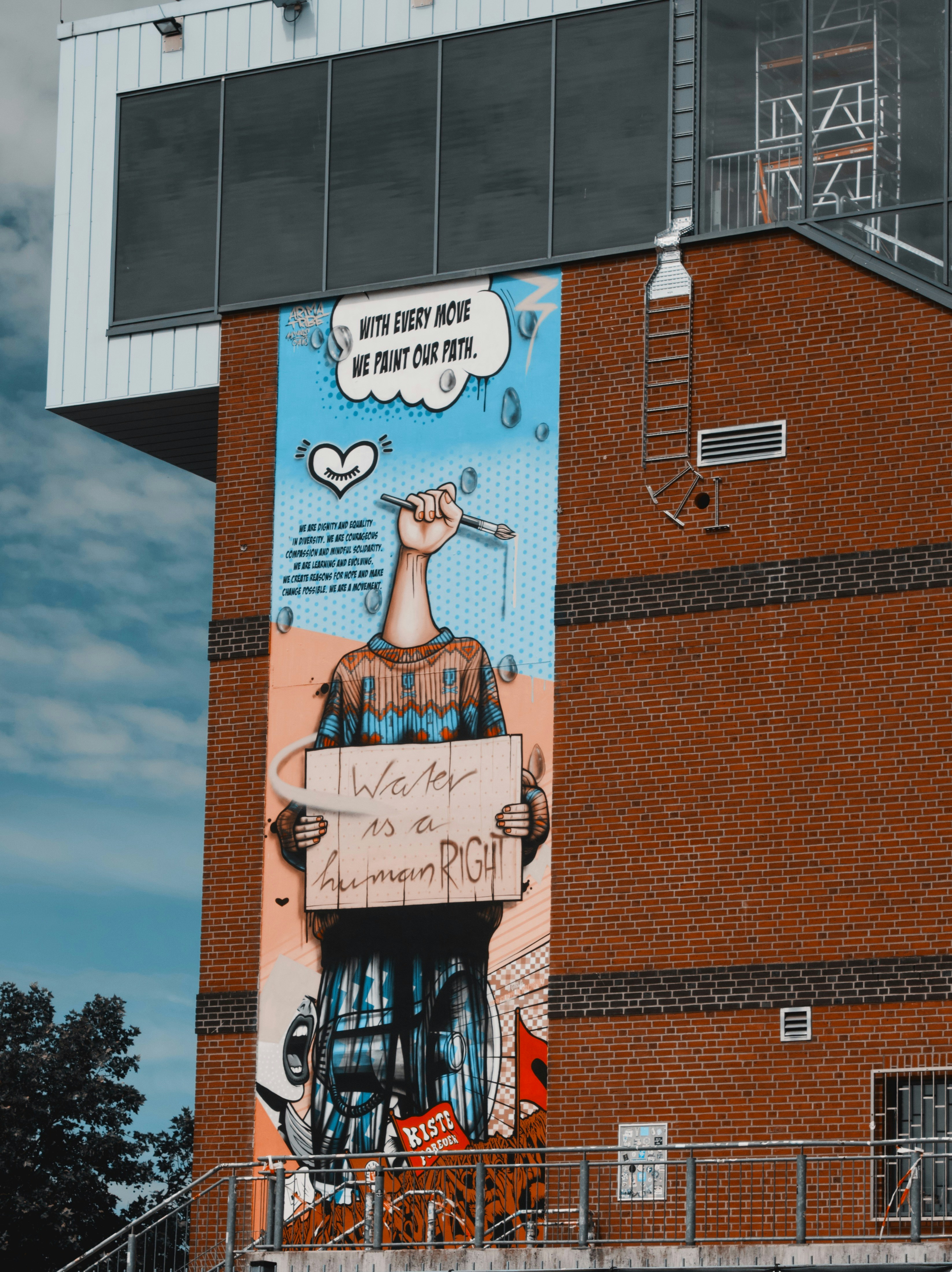 Mural Messenger: A Hoodie-Wearer Holding a Sign in Front of Brick Building