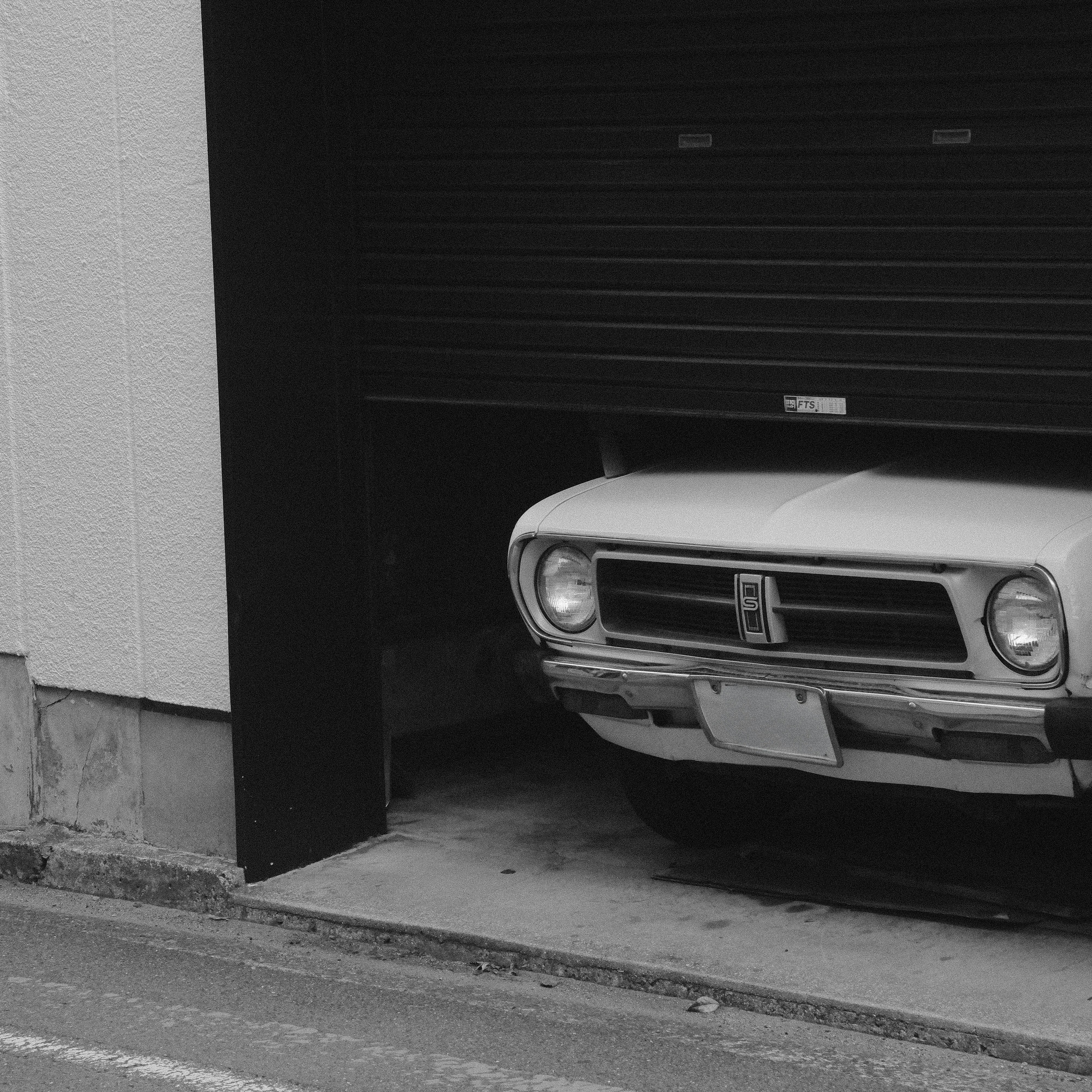 Grainy Garage Car: A Vintage Front Peeks from the Shadows