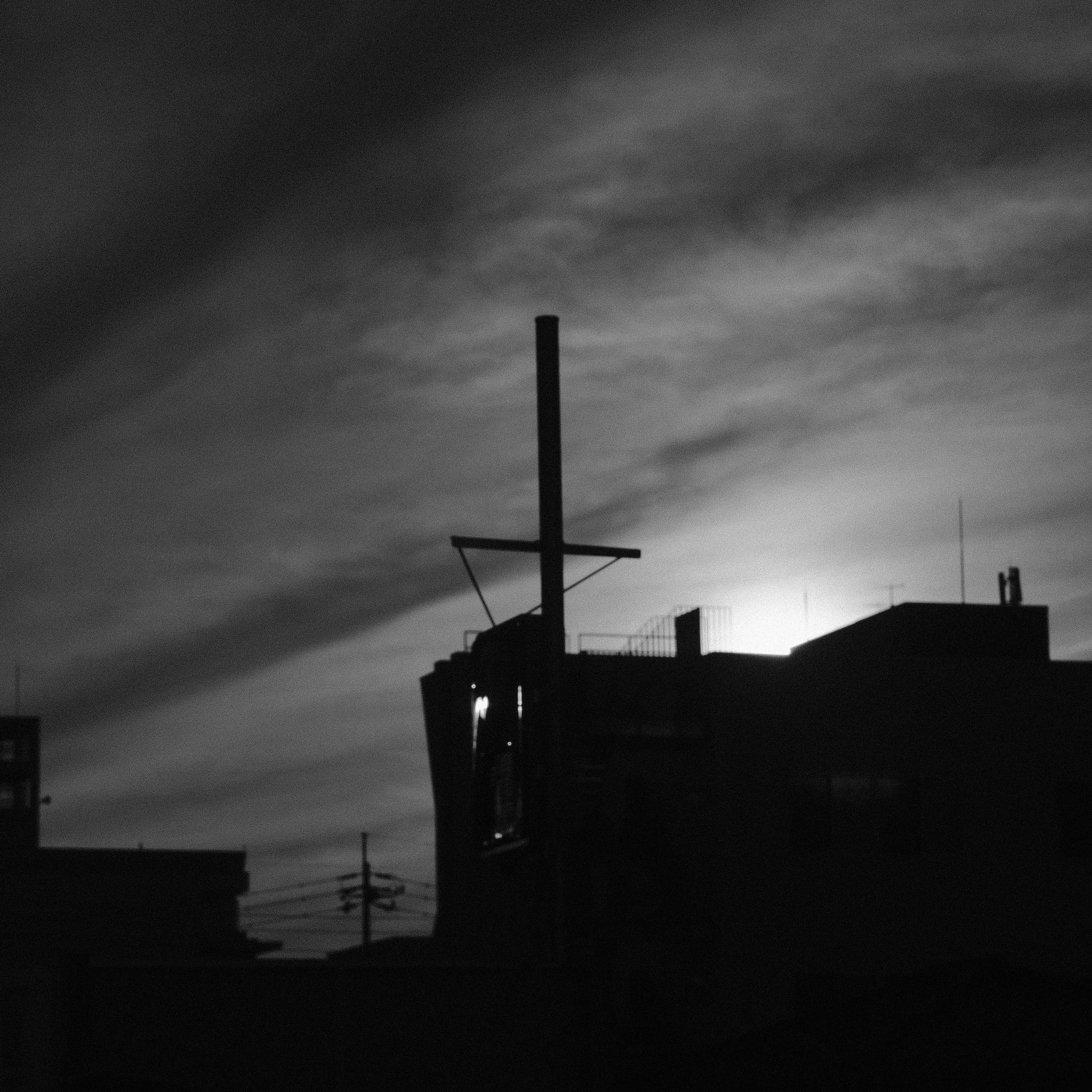 Silhouette at Dusk: A Rooftop Cross Against a Quiet Sky