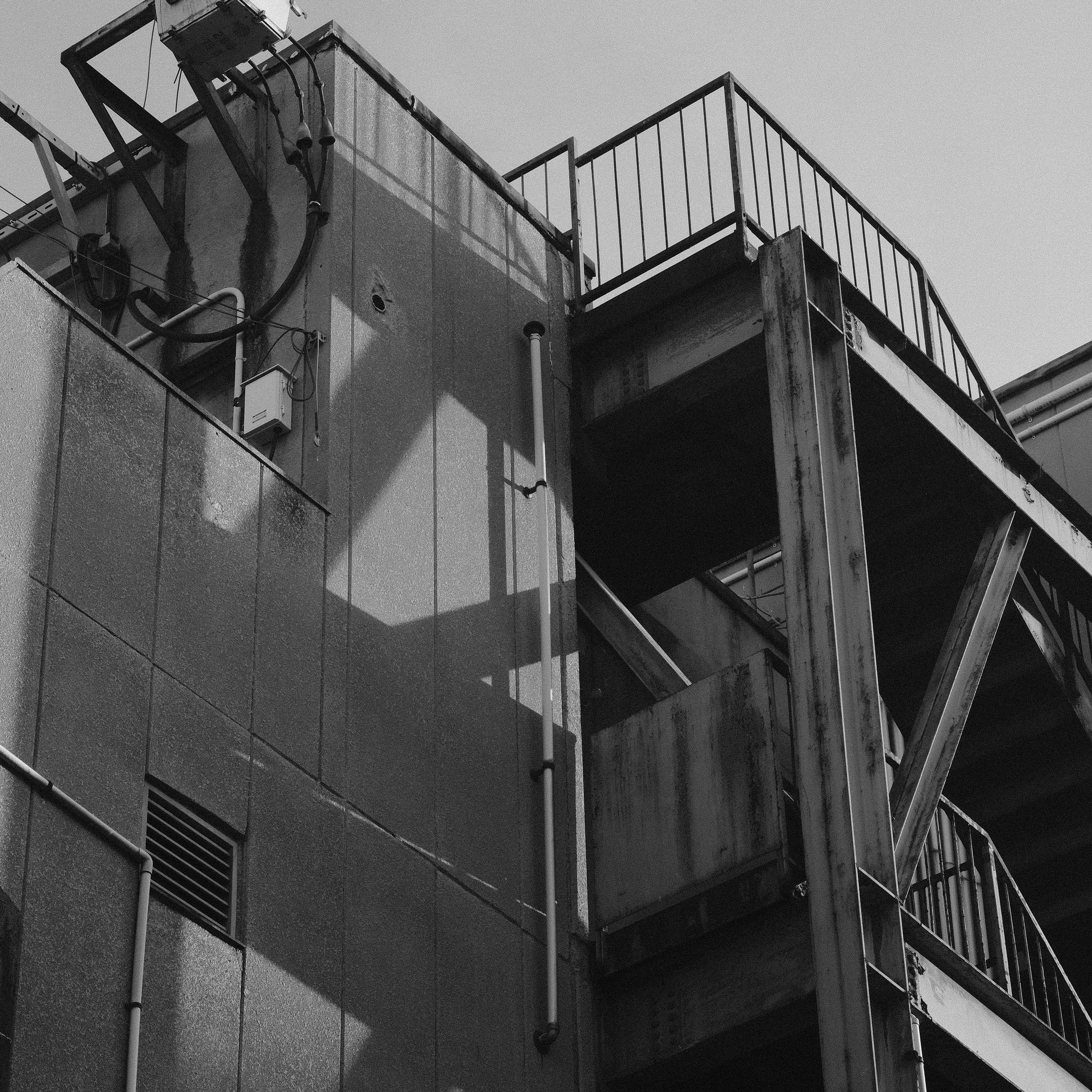 Industrial Sidewalk Echoes: A Stairwell Bows to Steel Gravity