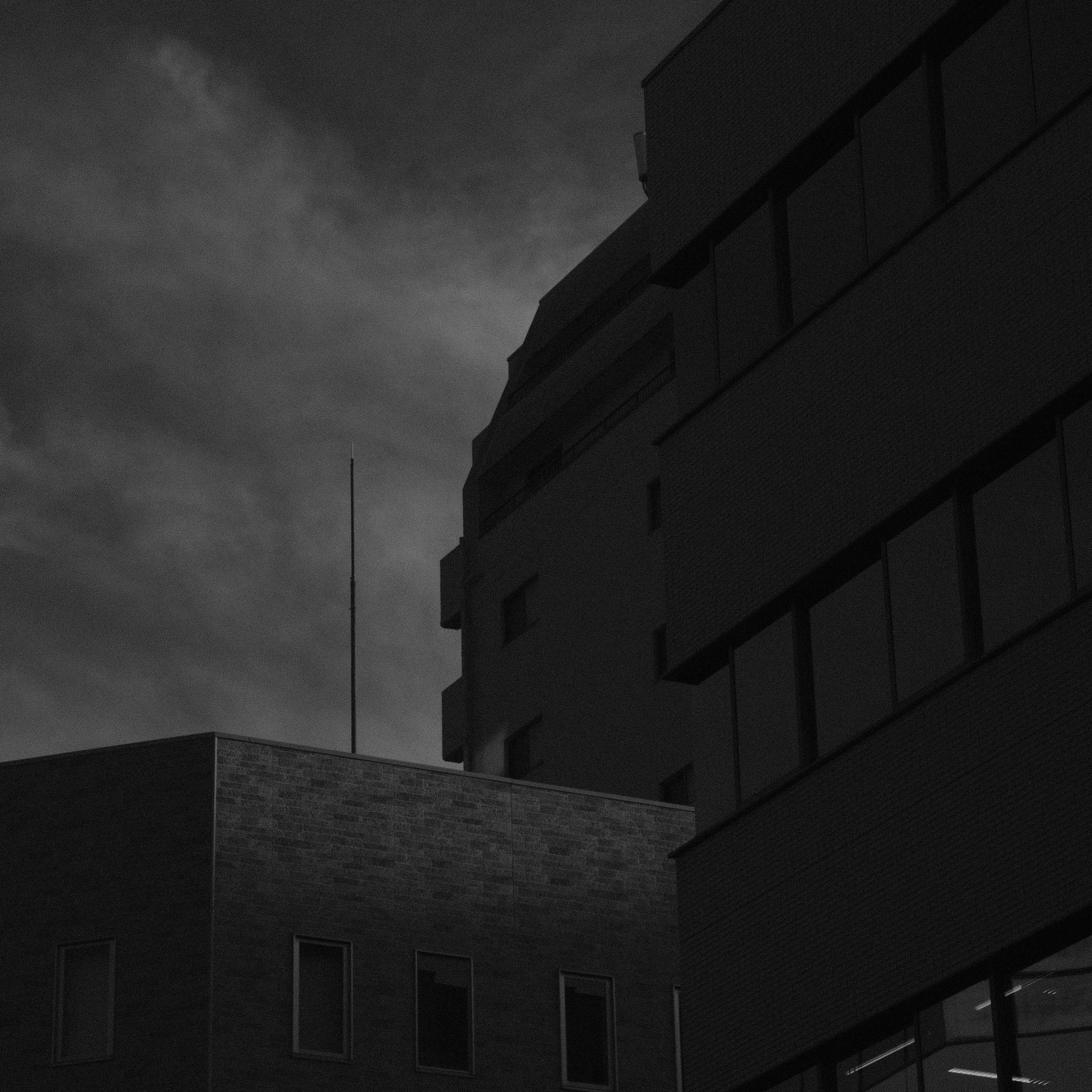 Dark buildings under a cloudy, monochromatic sky.