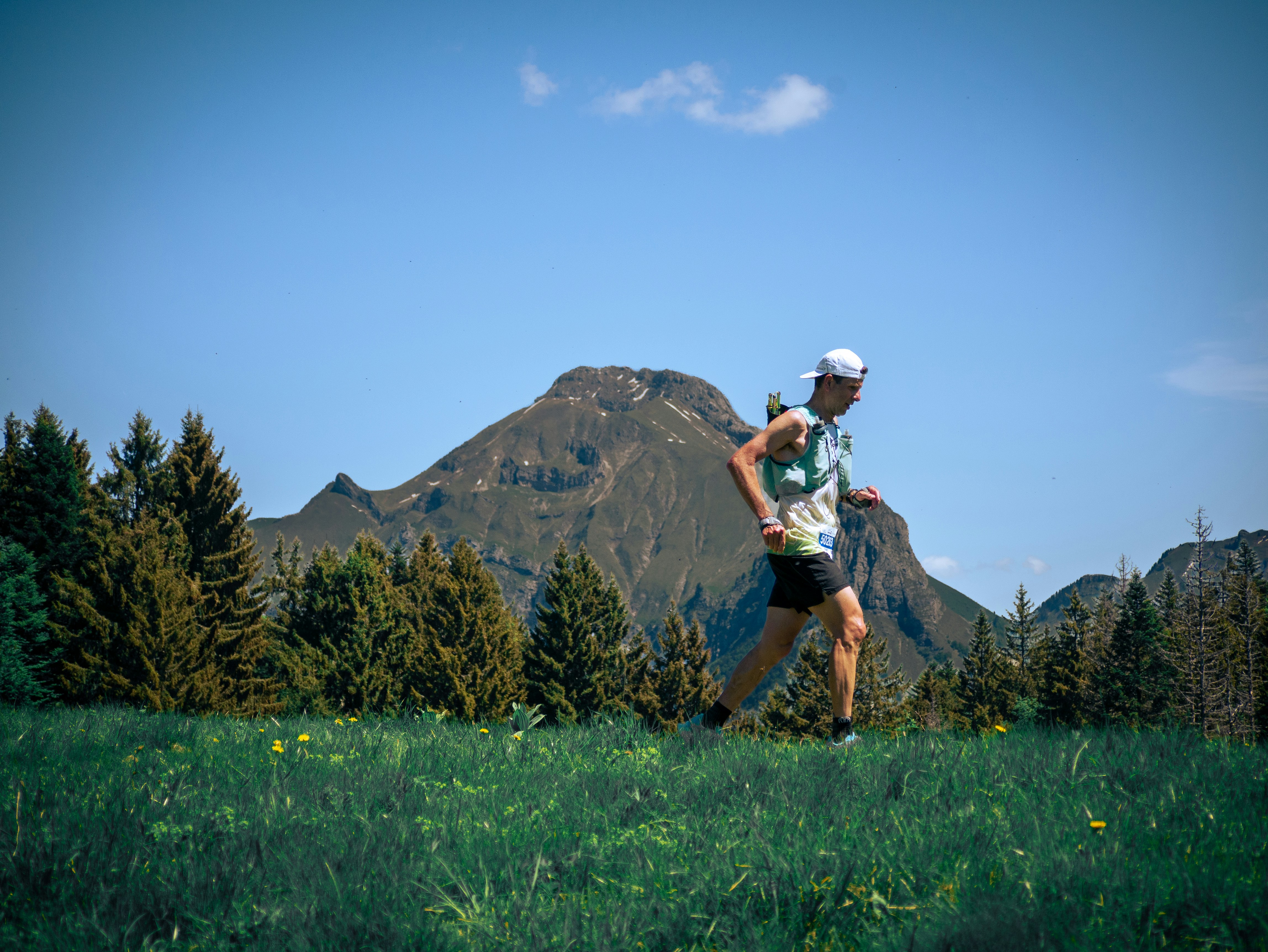 Man trail running on a sunny mountain landscape.