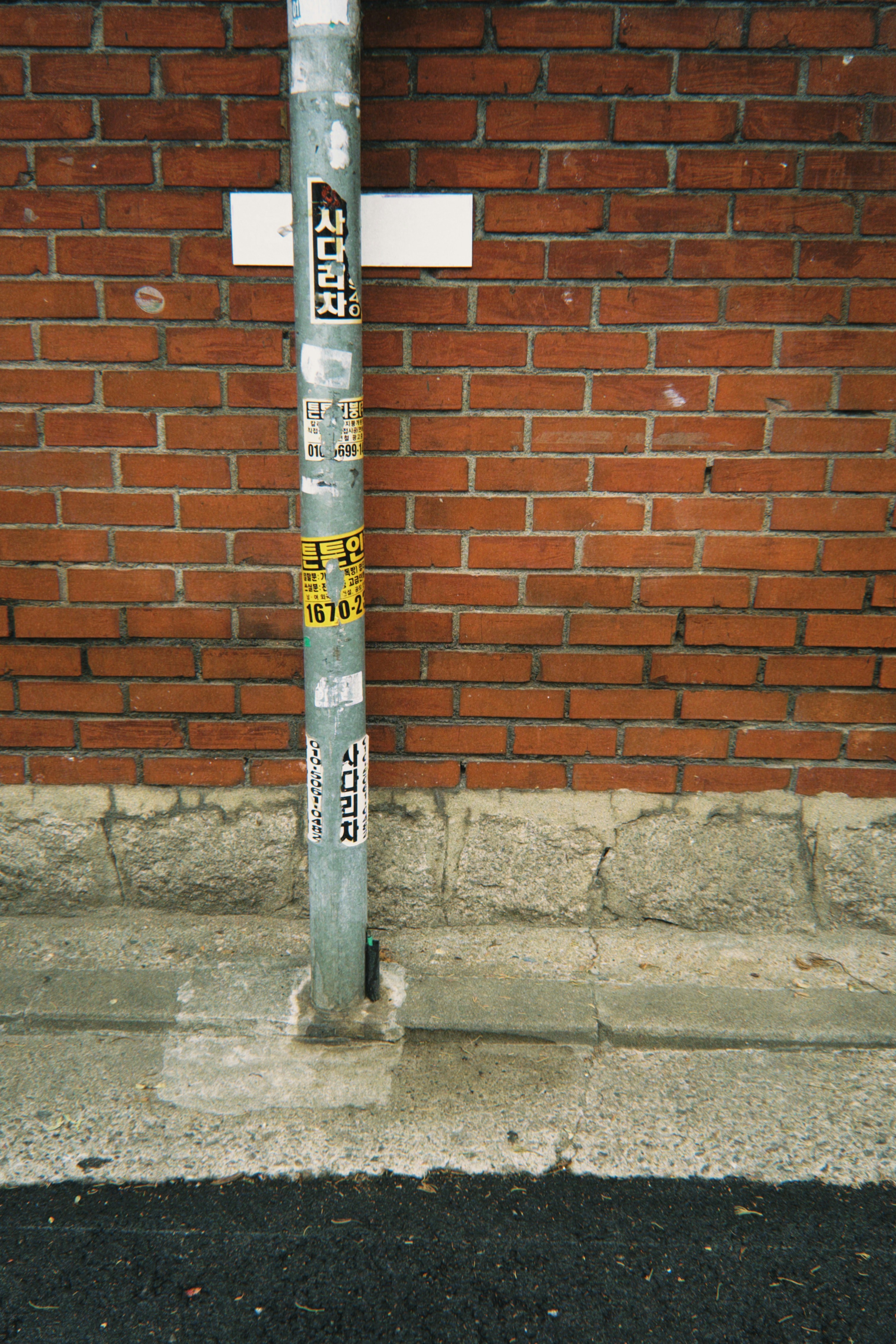 Message on a Wall: A Single Metal Pole Anchored by a Brick Backdrop