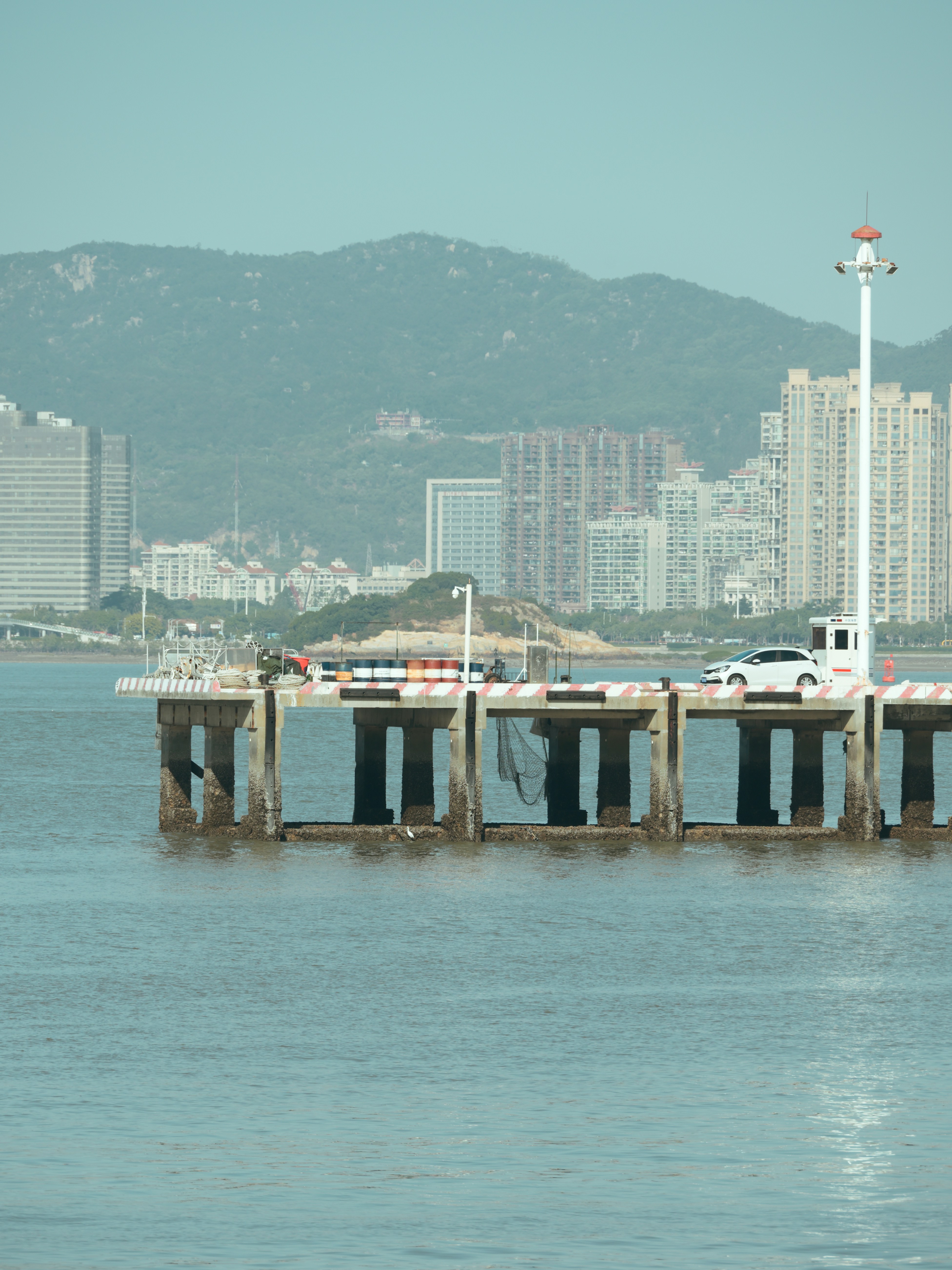 Pier at the Coastal City: Cars, Light Poles, and Distant Towers