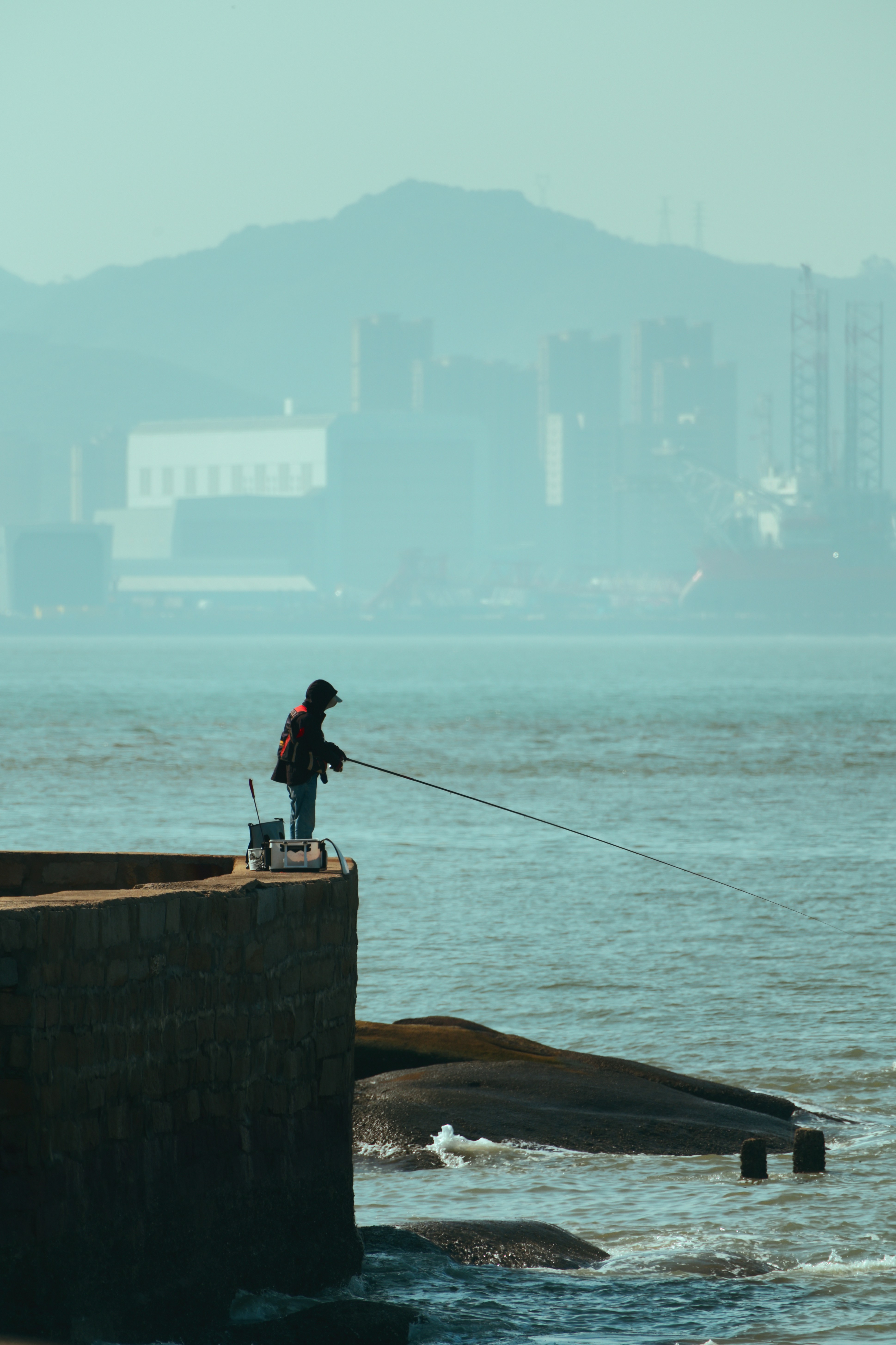 Rimward Fisher: A Lone Angler at the Edge of Calm Seas