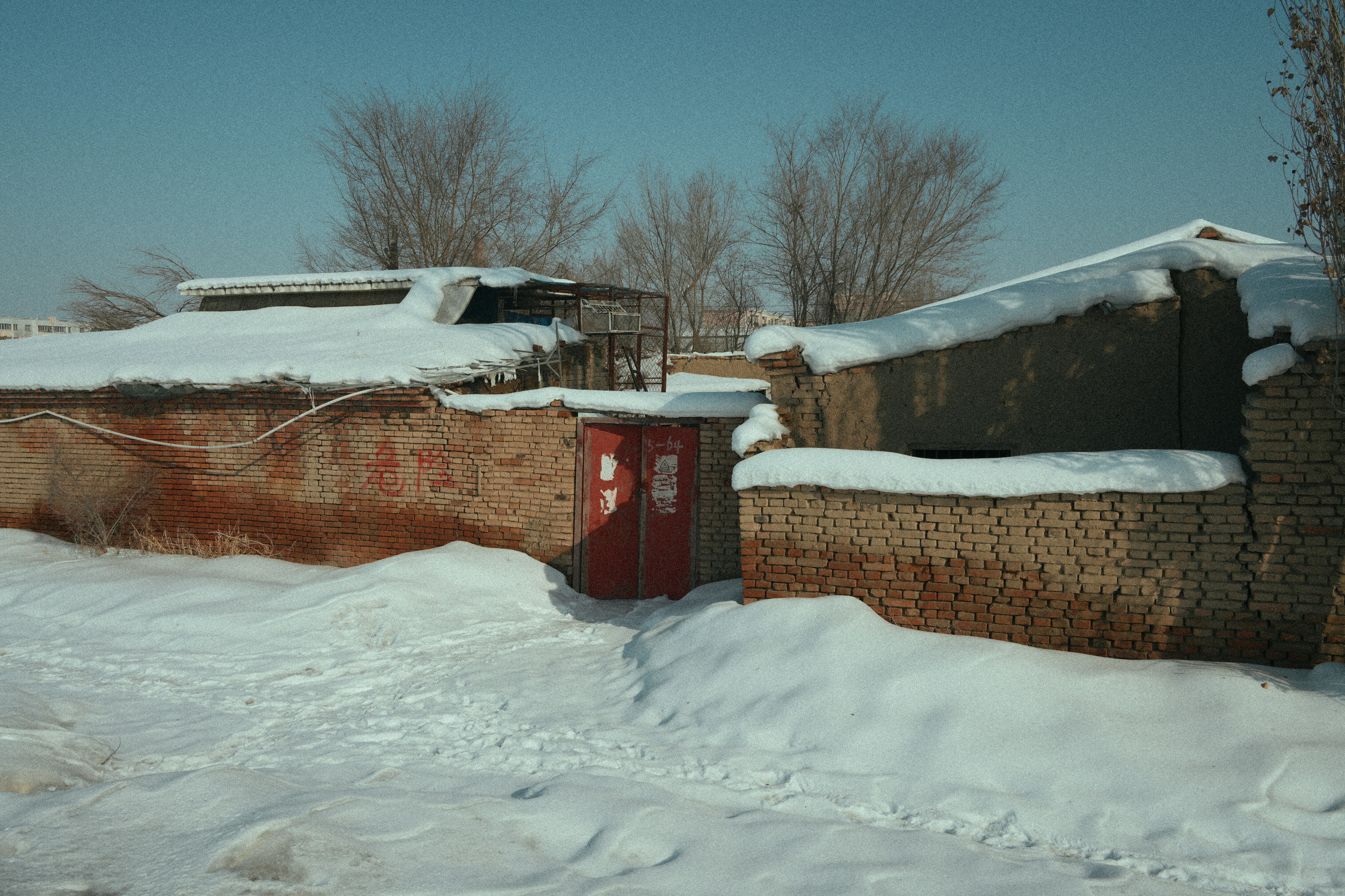 Snowbound Brickwork and Red Gate Beyond a Quiet Yard