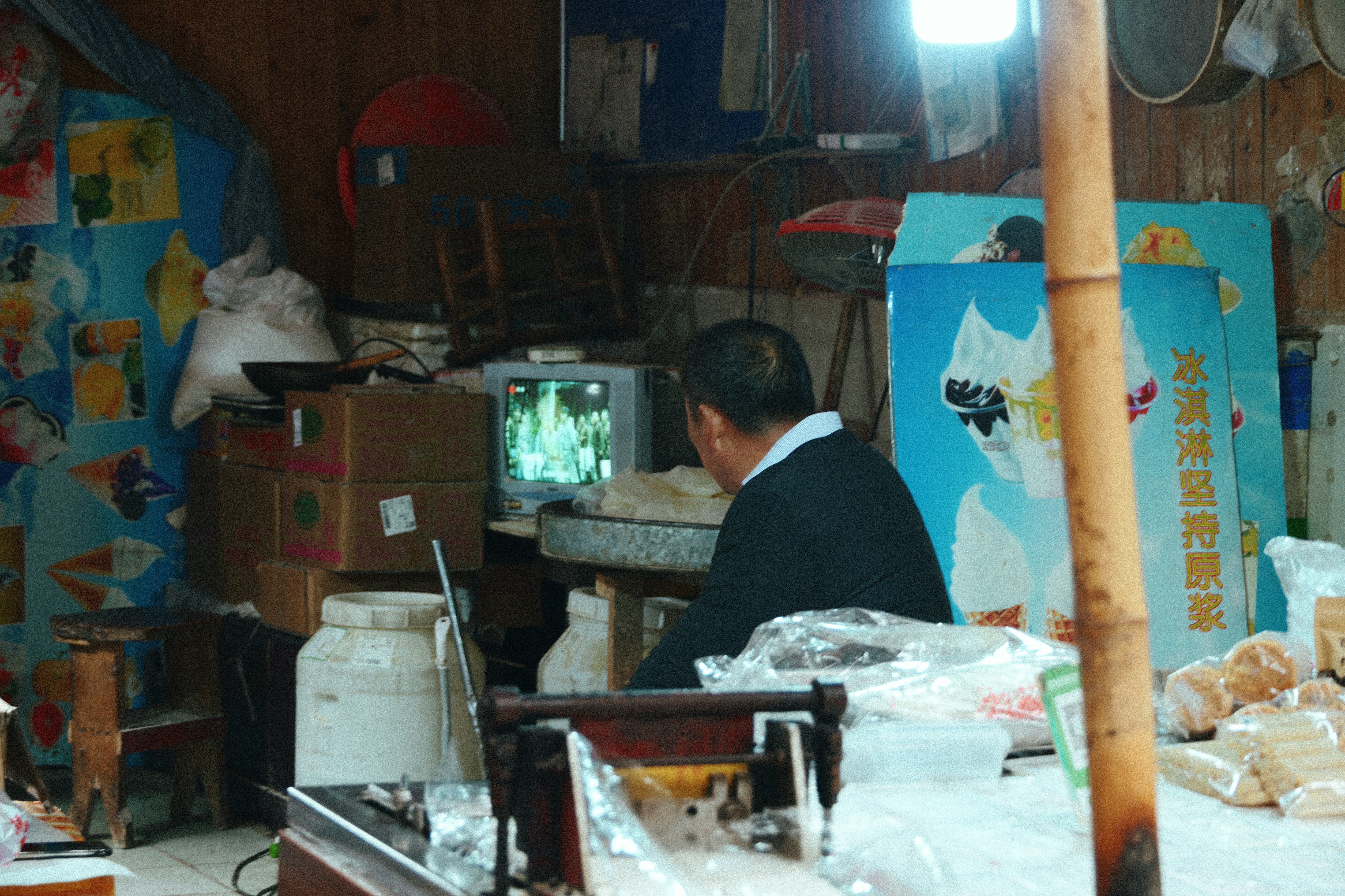 A person watches an old television in a cluttered room.