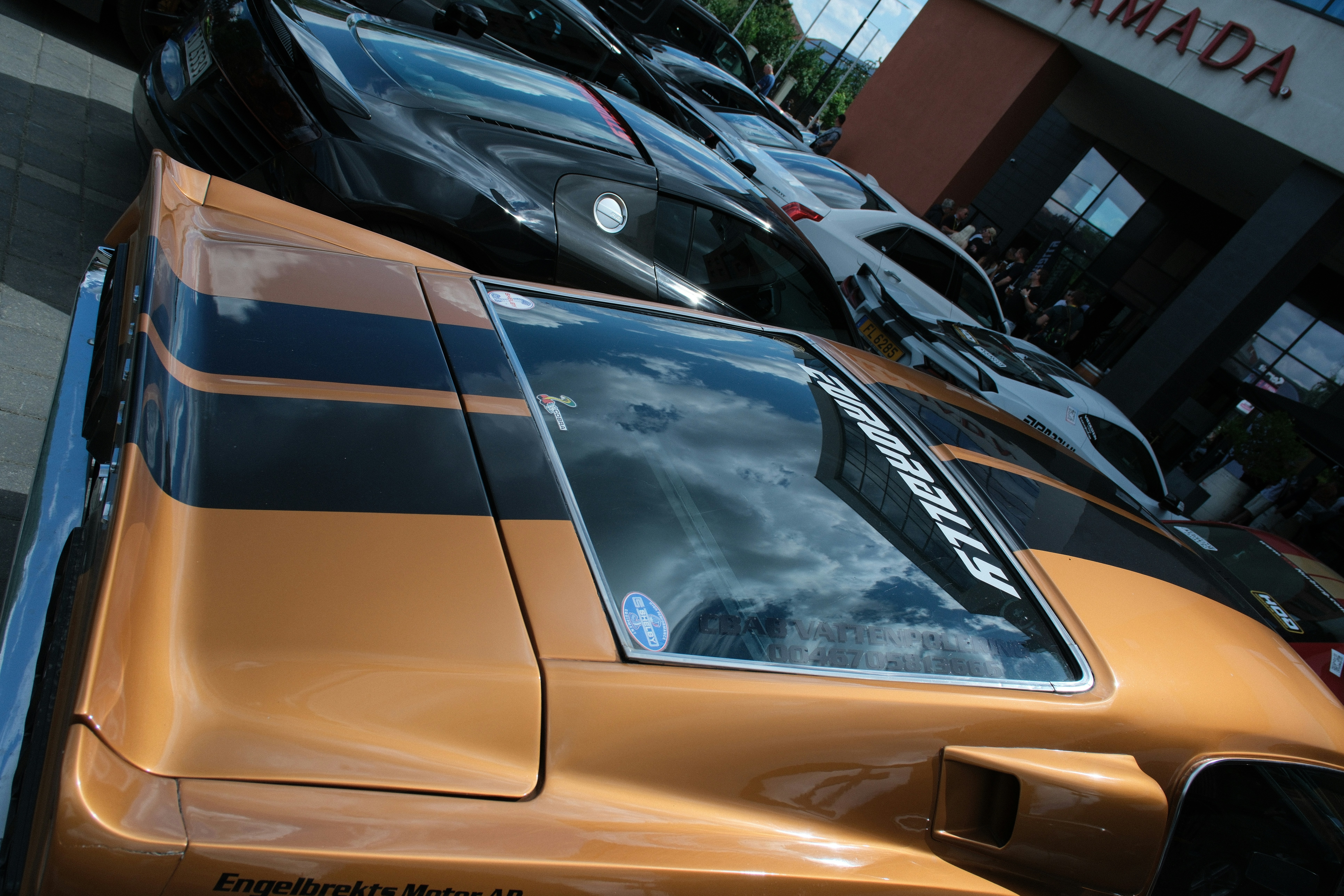 Gold and black Mopar Hood: reflected sky and showroom lineup