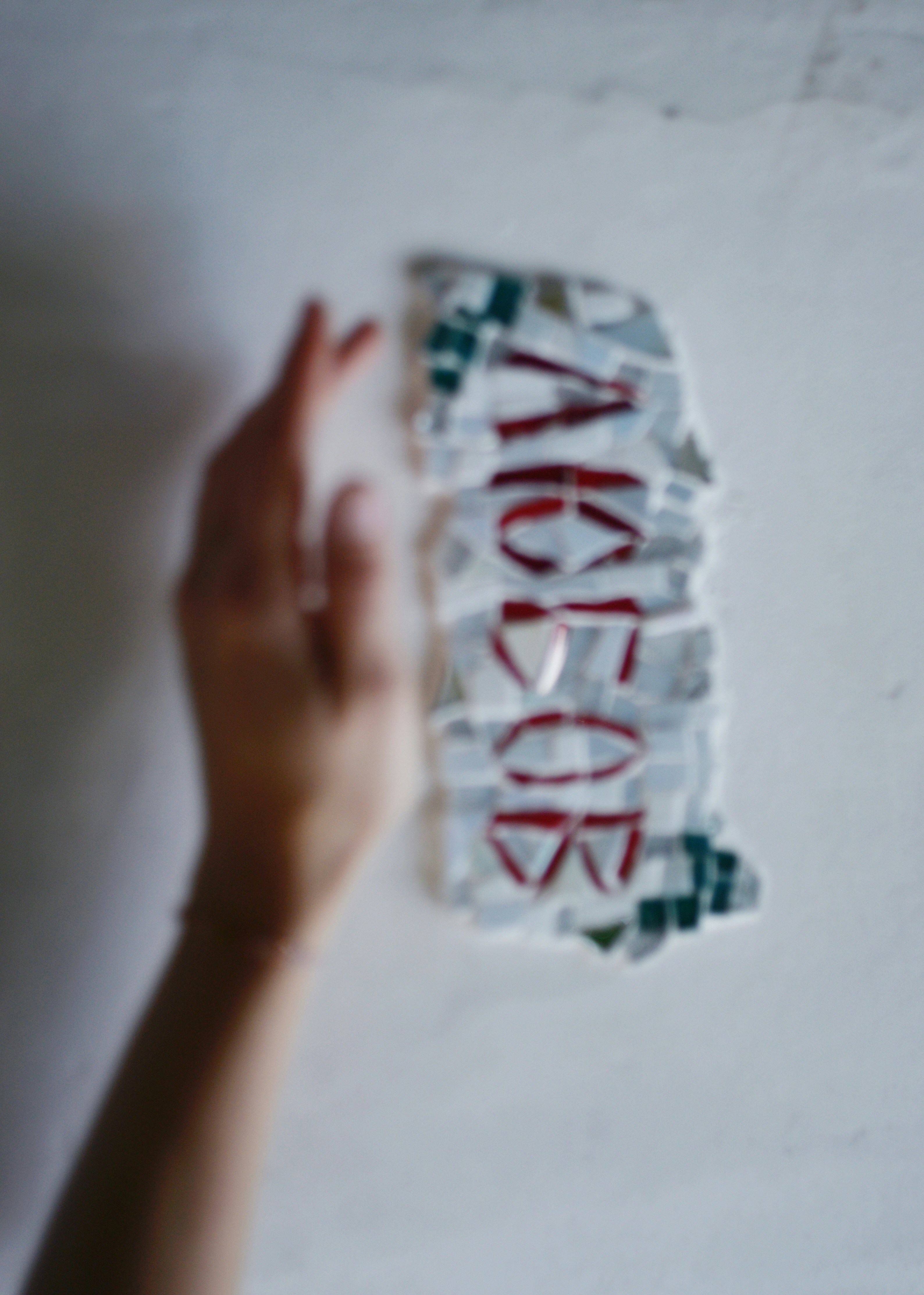 Fractured mural of 'LOVE' with a soft-focused hand reaching toward the center