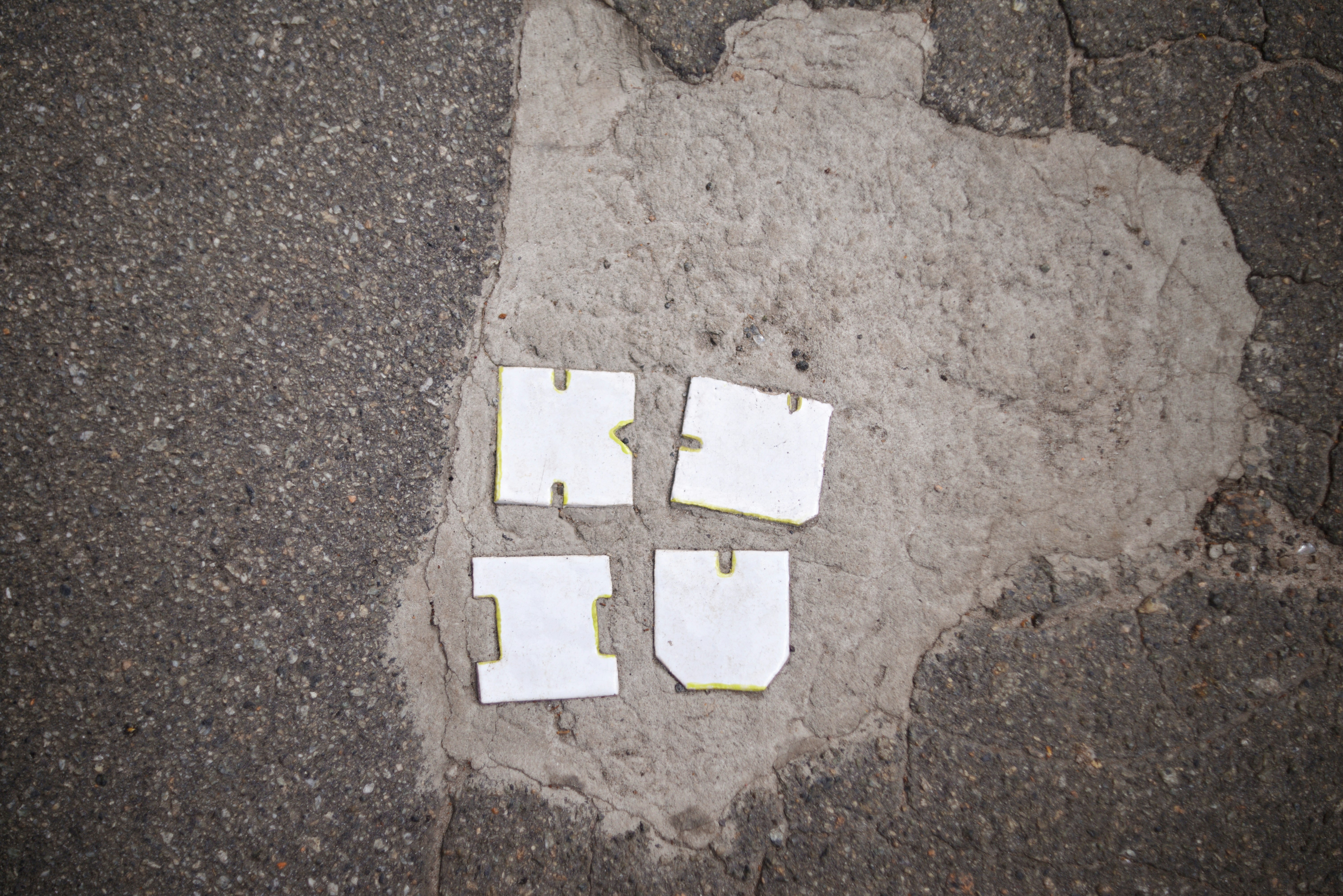 Fragmented white stickers on weathered asphalt pavement