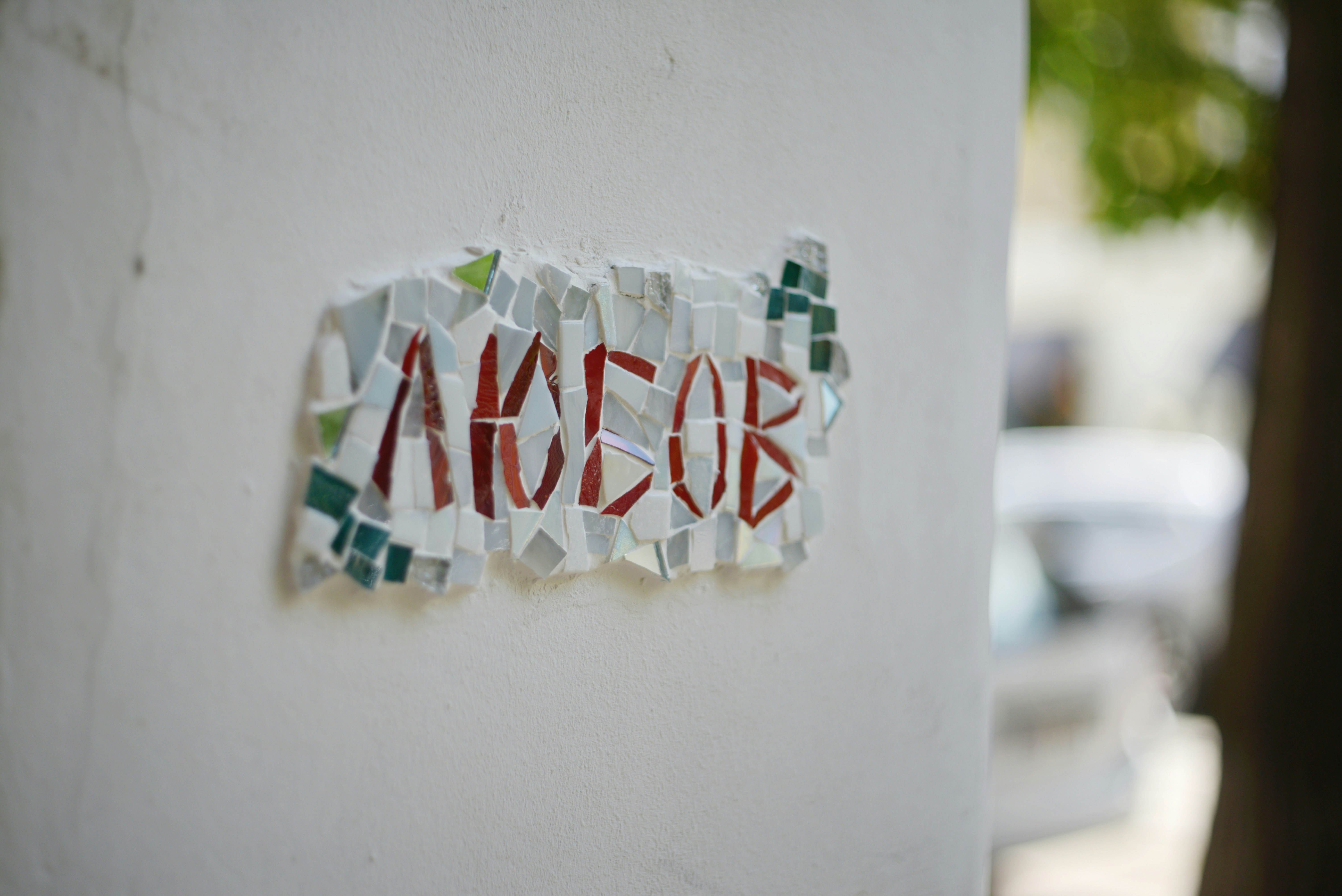 Mosaic sign on a sunlit street wall