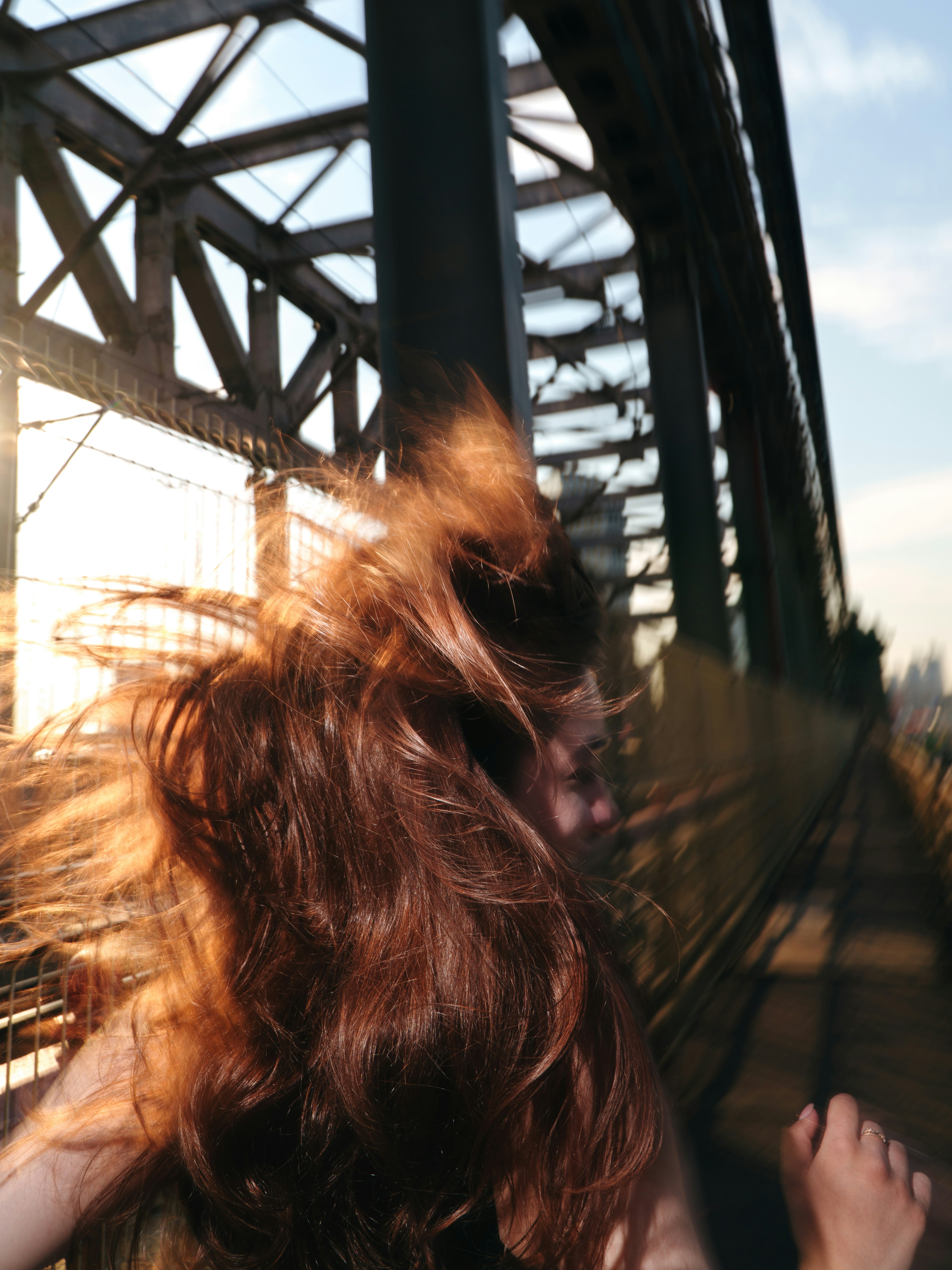 Wind-tossed portrait on a sunlit bridge