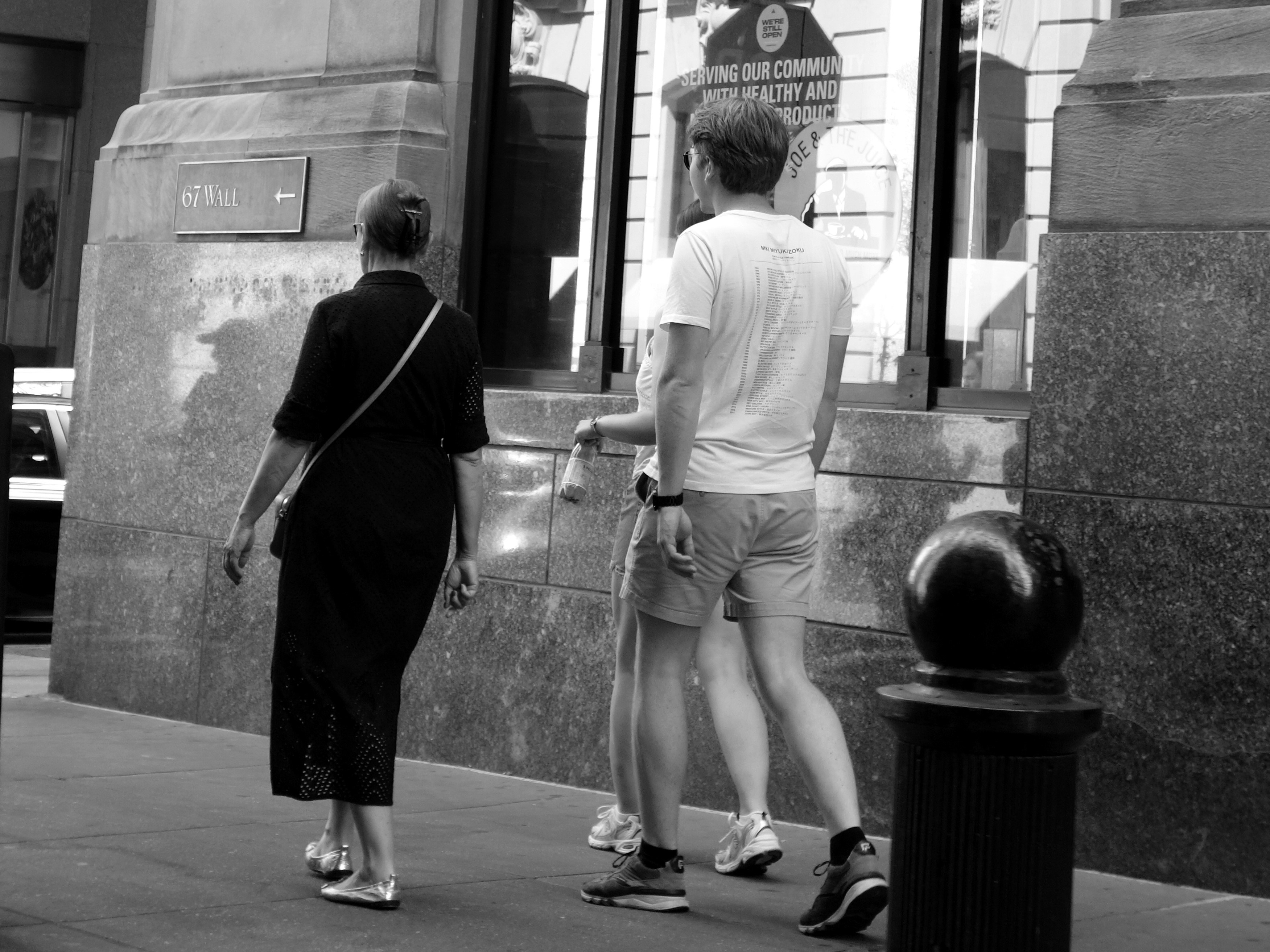 Two people walking on a city sidewalk past a building.
