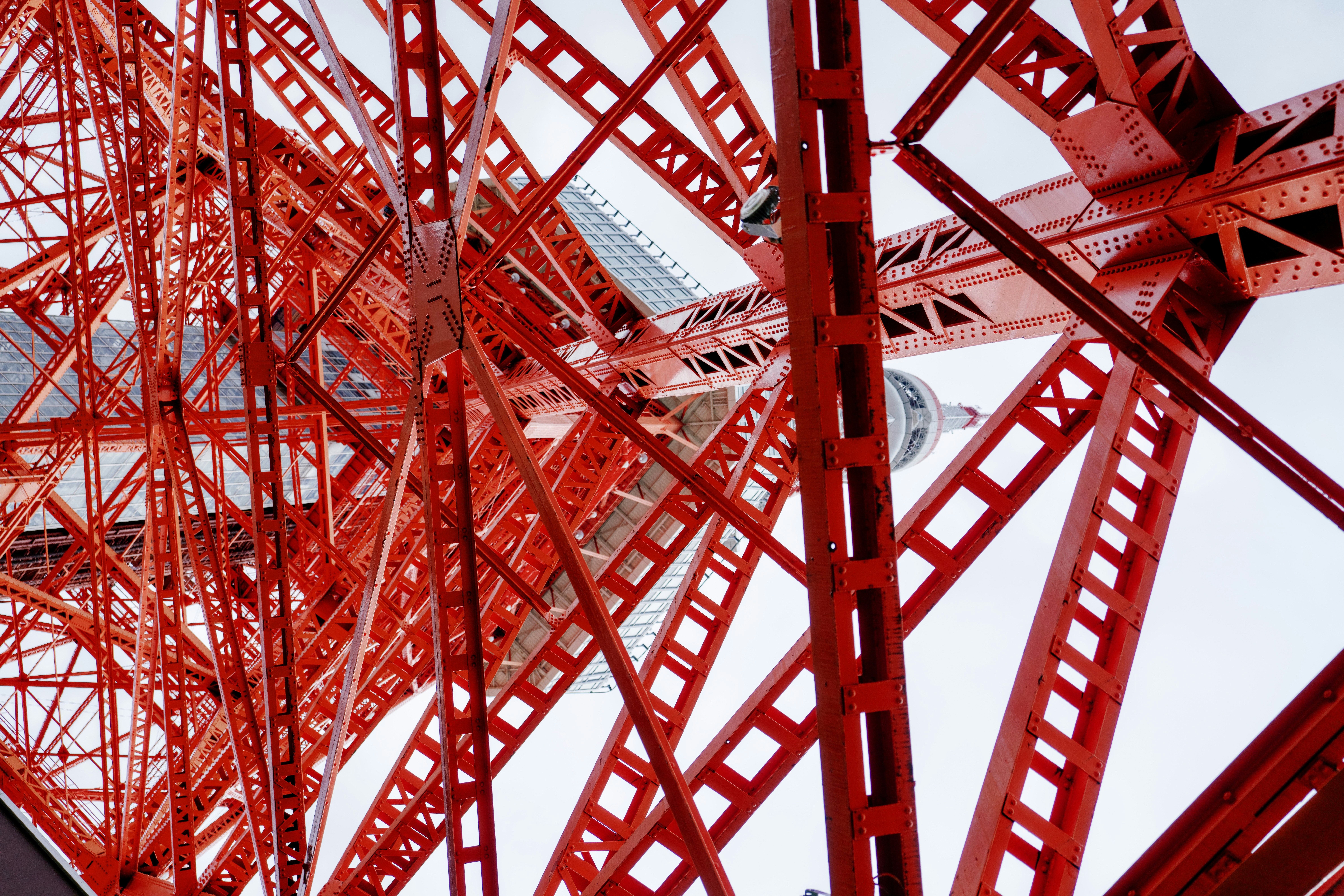Red steel framework of a tower against a bright sky.
