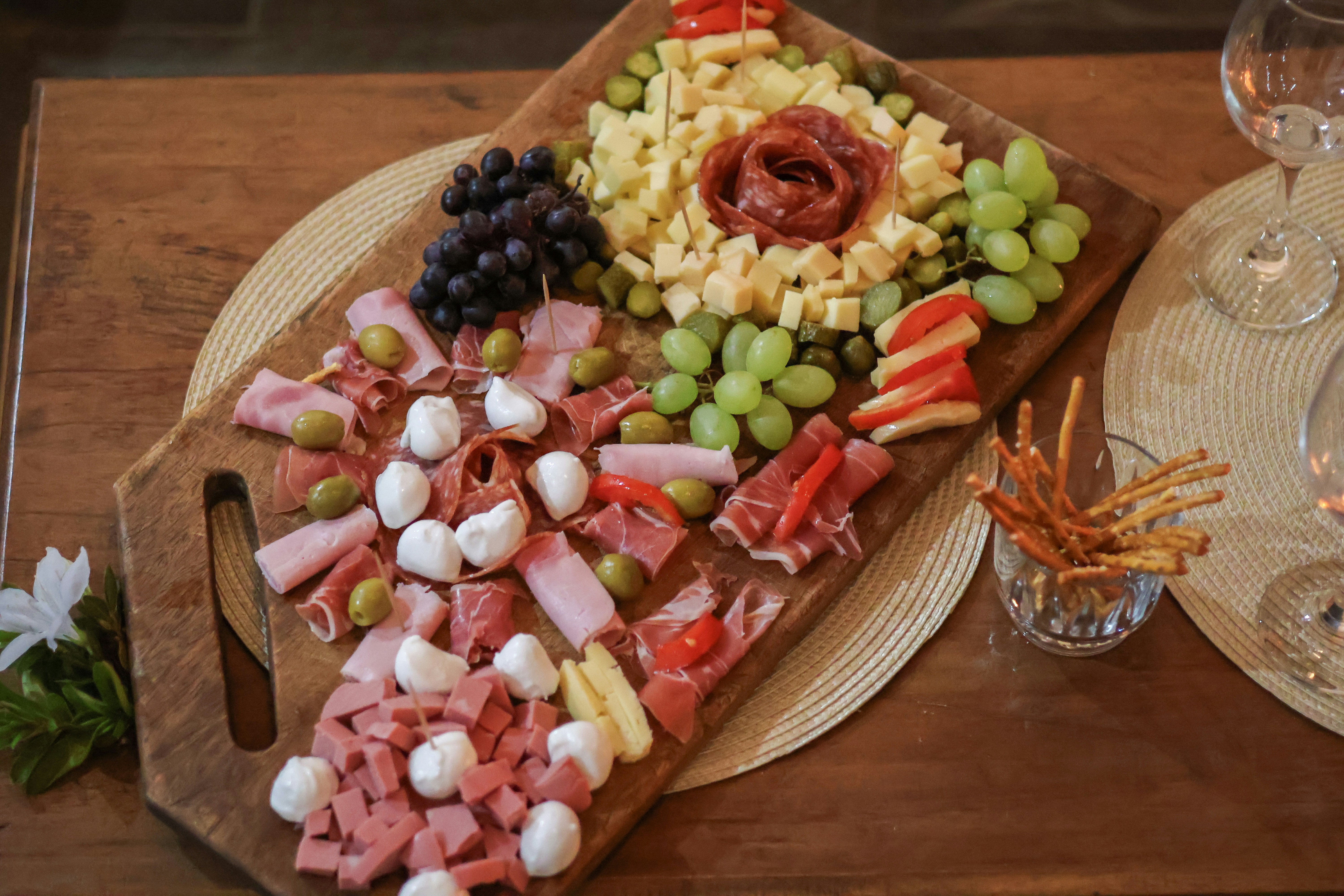 Elegant charcuterie board featuring cheeses, cured meats, grapes, olives, and wine, creating a cozy dining experience in Gonçalves, Minas Gerais, Brazil.