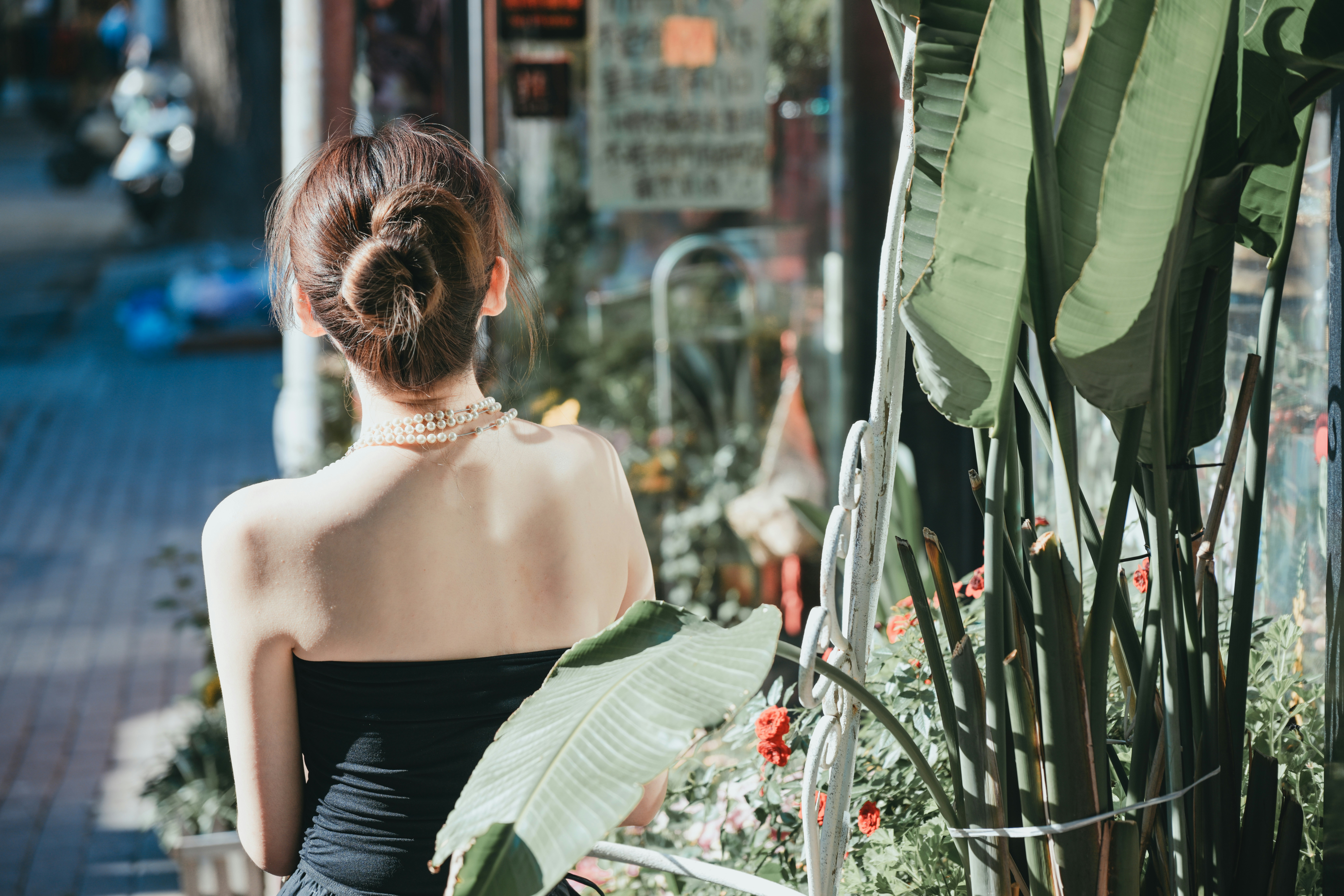 Elegant woman with pearl necklace looking at a shop window.