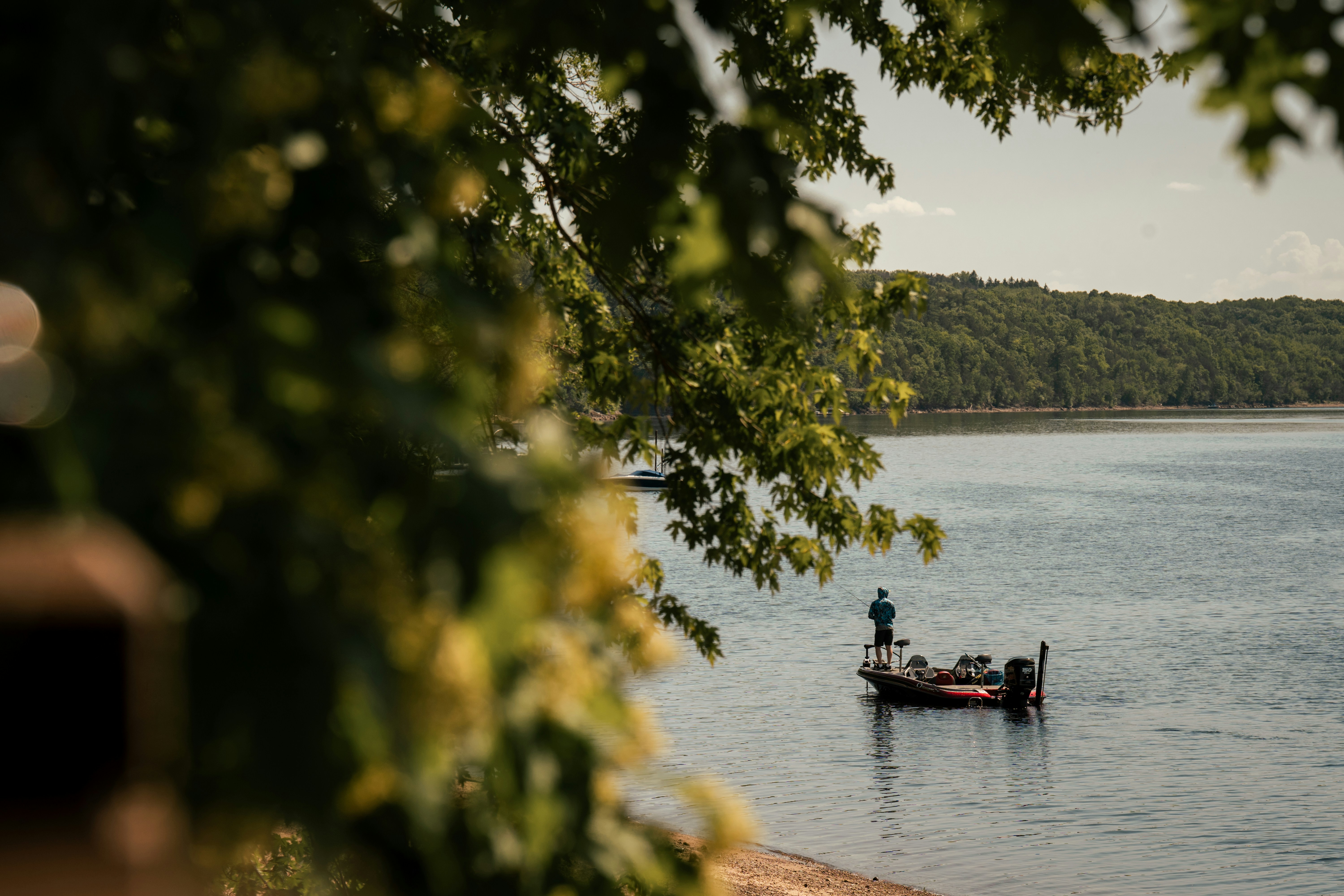 Serene lakeside netting at sunset: a lone fisherman and boat