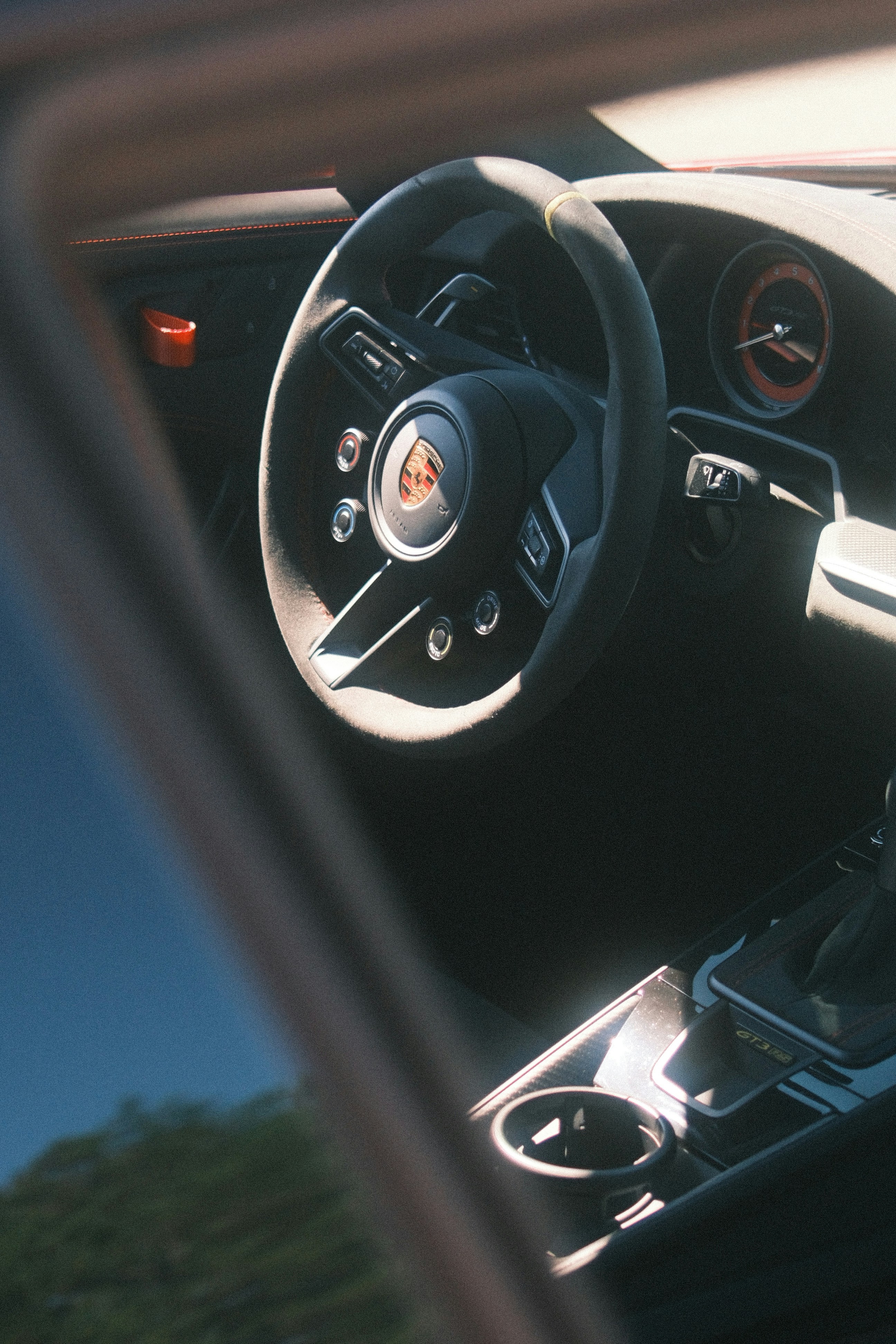 Porsche car interior showing steering wheel and dashboard.