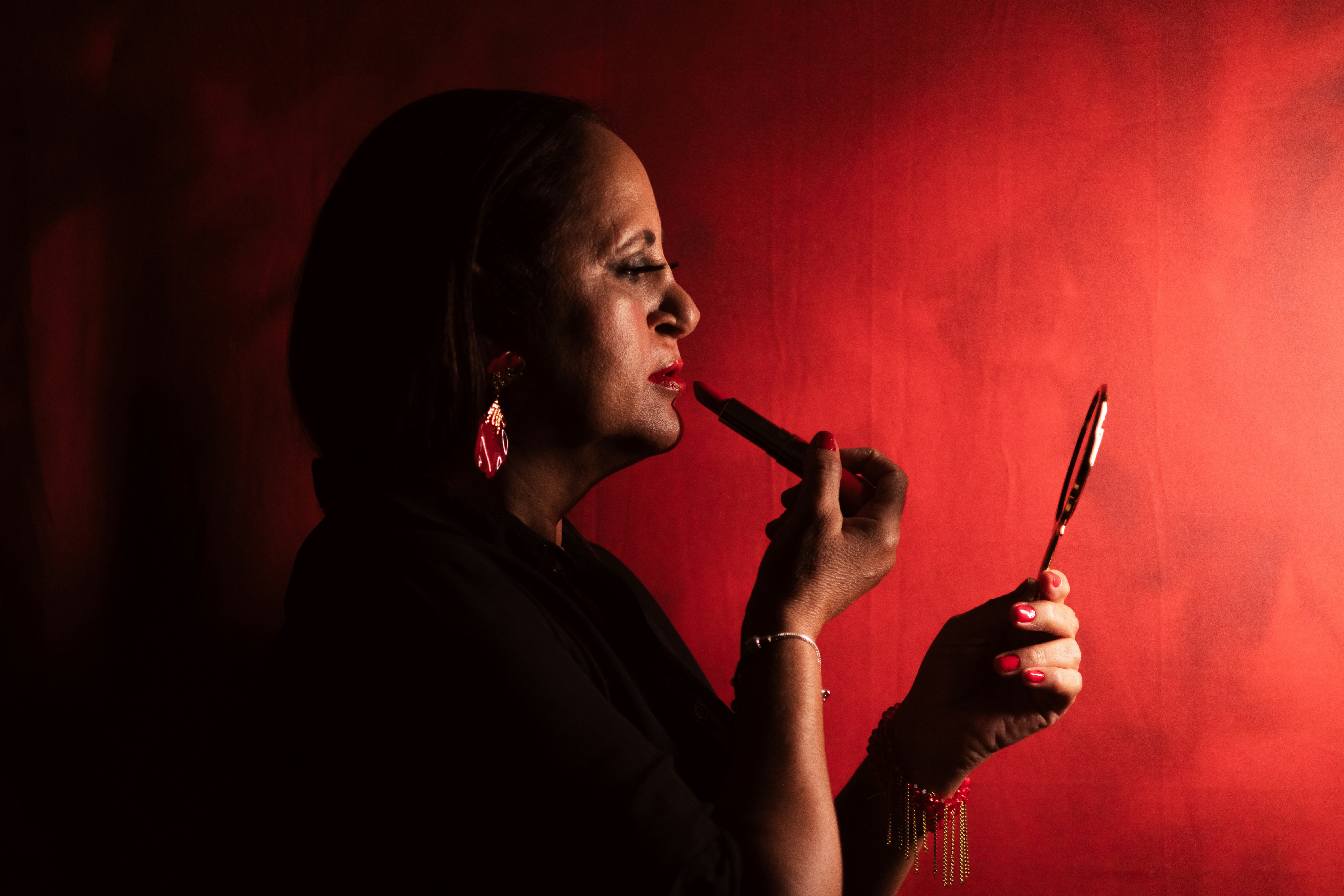 Red-lit reflection: a poised gaze at the lipstick touch