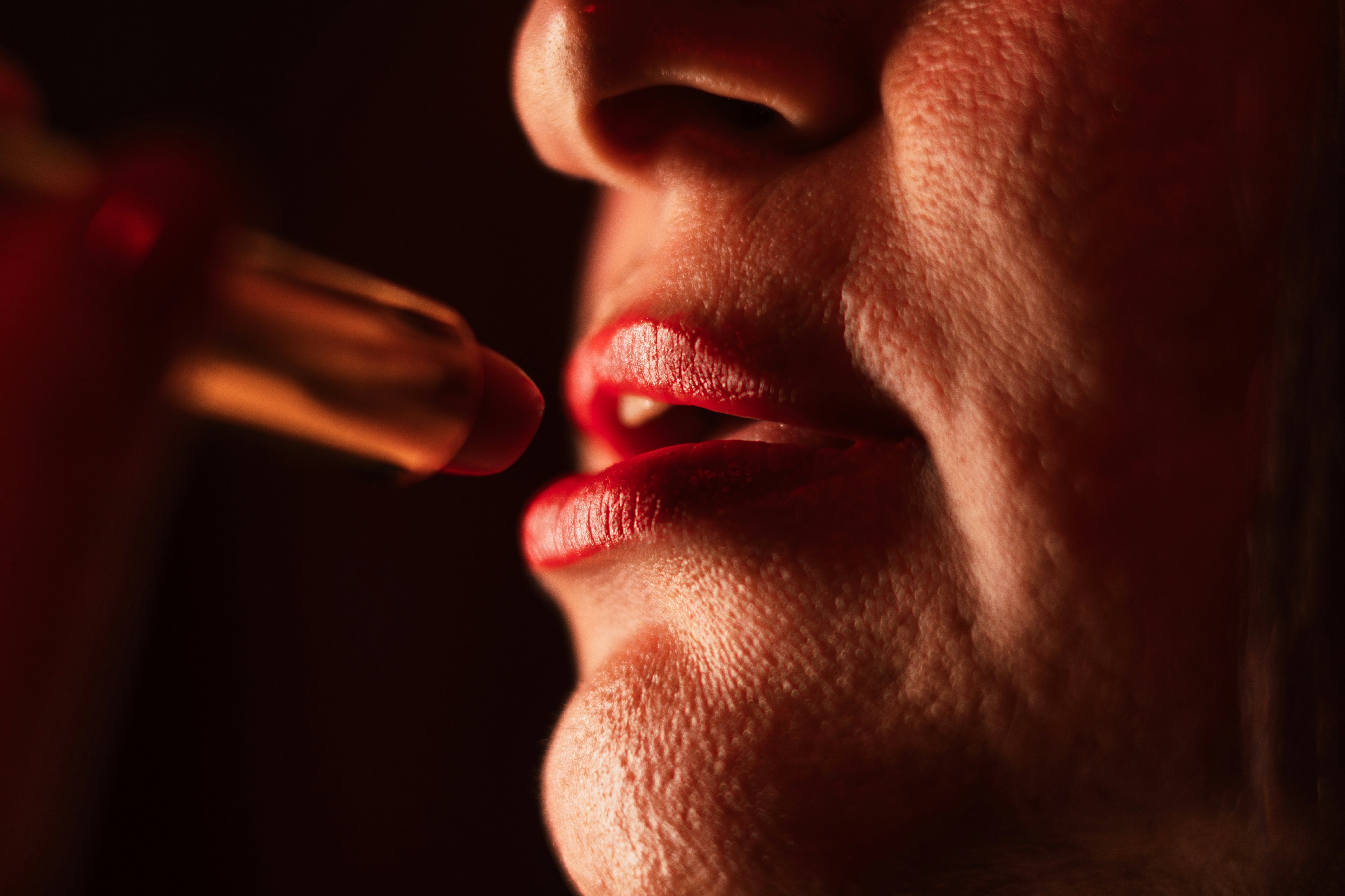 Lip Art in Red Light: A Close-Up of a Whispered Bite