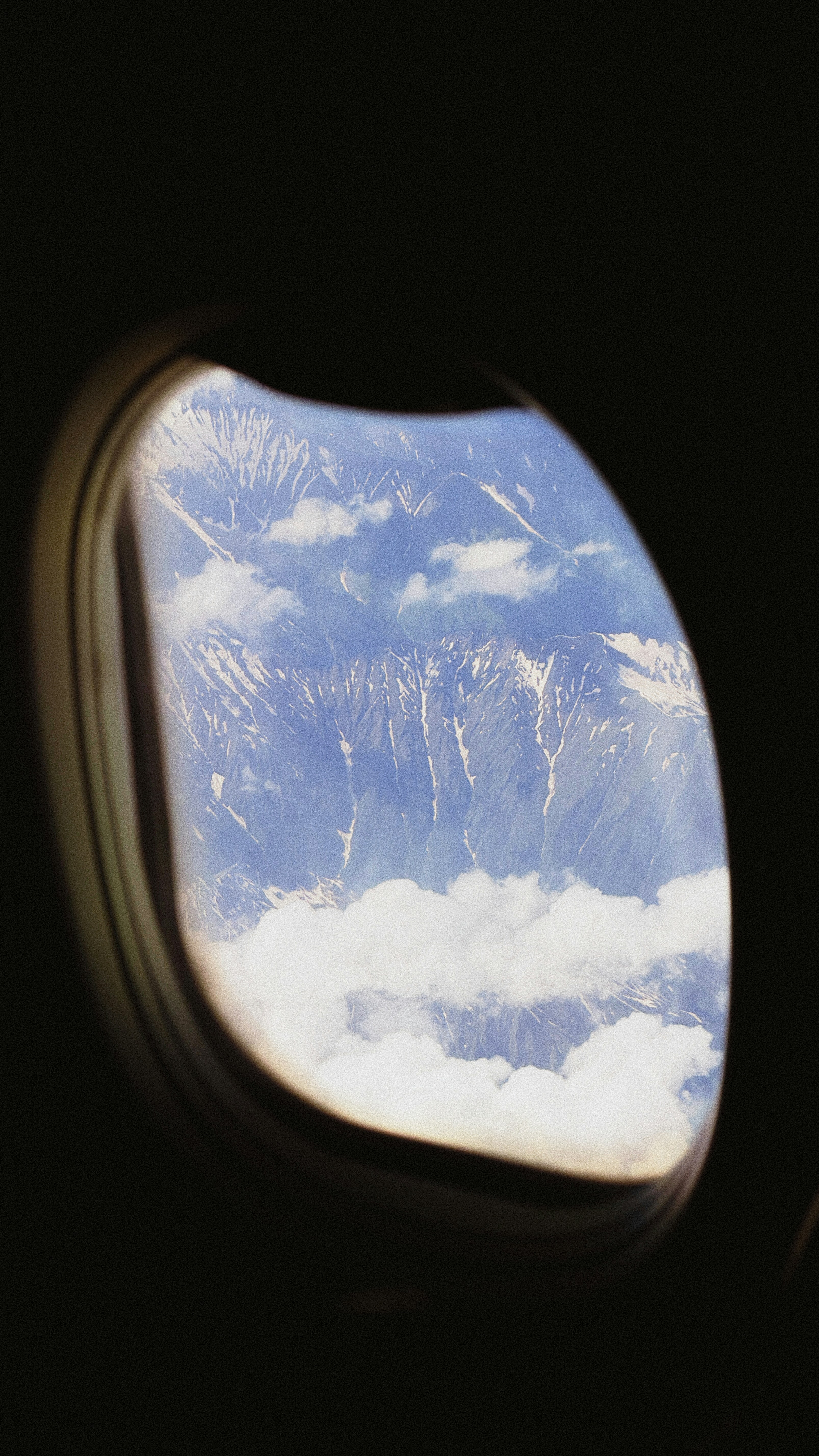 Sky-Blue Rim: Mountain Cloudscape Through an Airplane Window