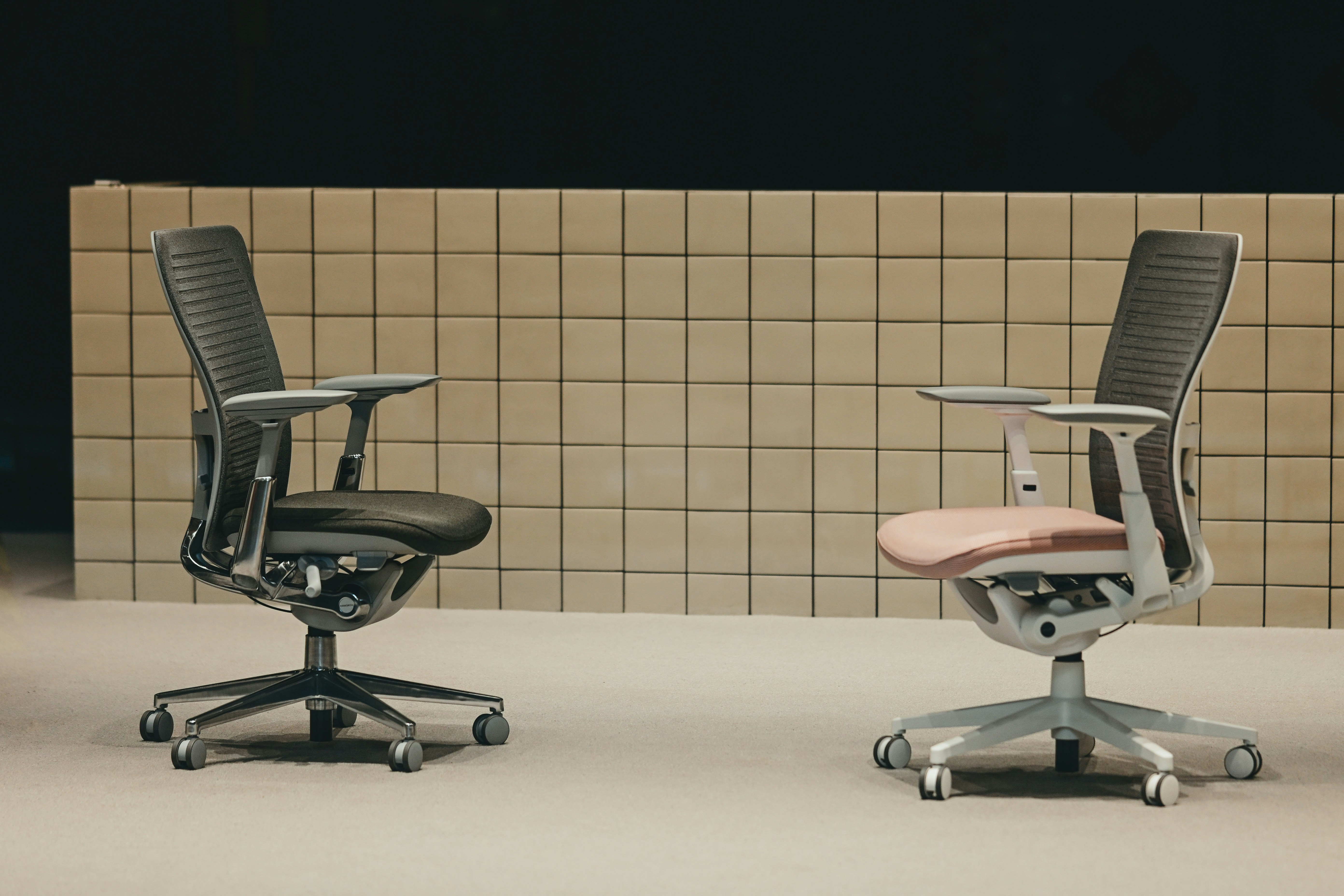 Two ergonomic office chairs, dark and light, facing each other.