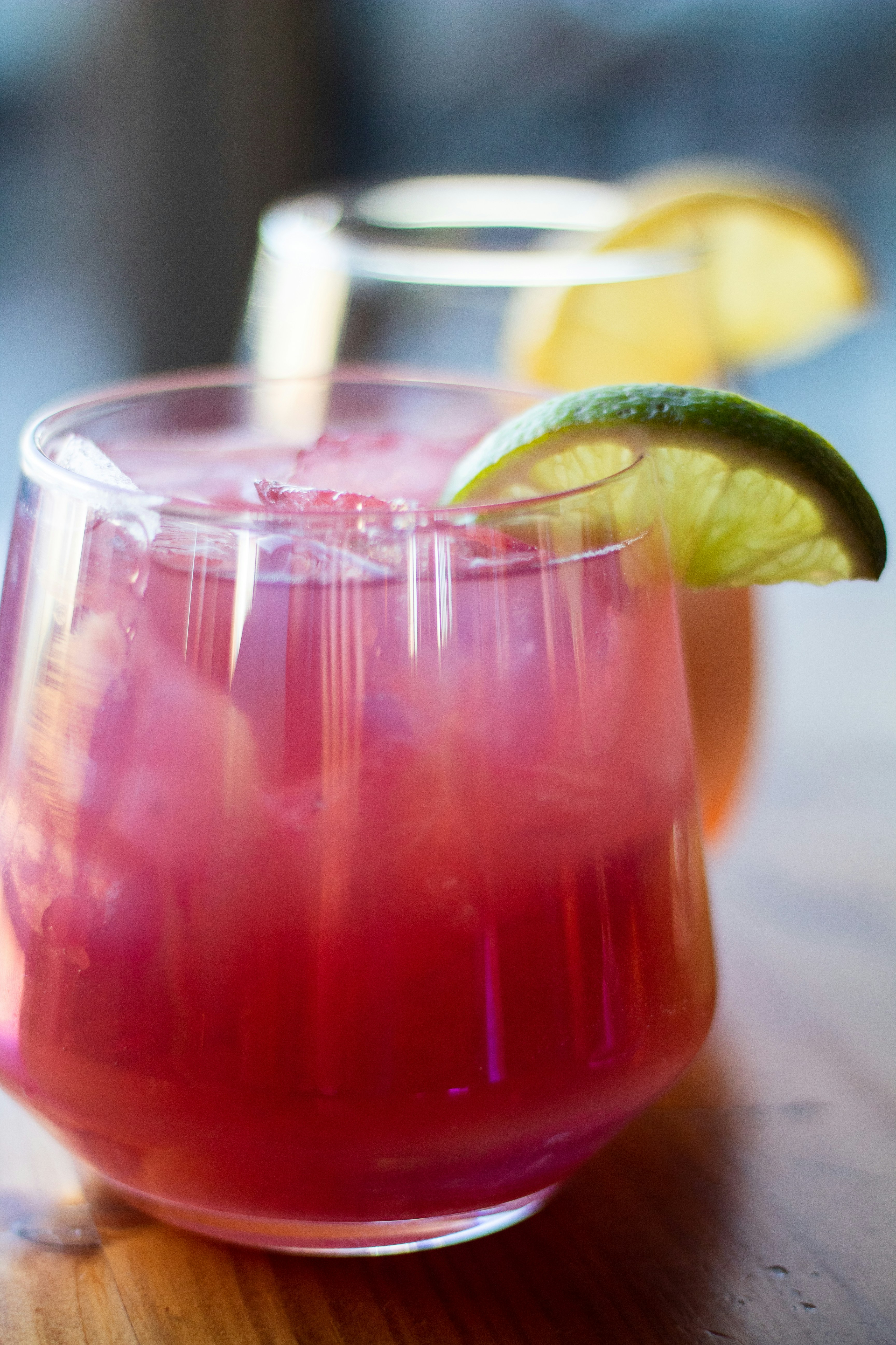 Pink cocktail in a rounded tumbler crowned with lime