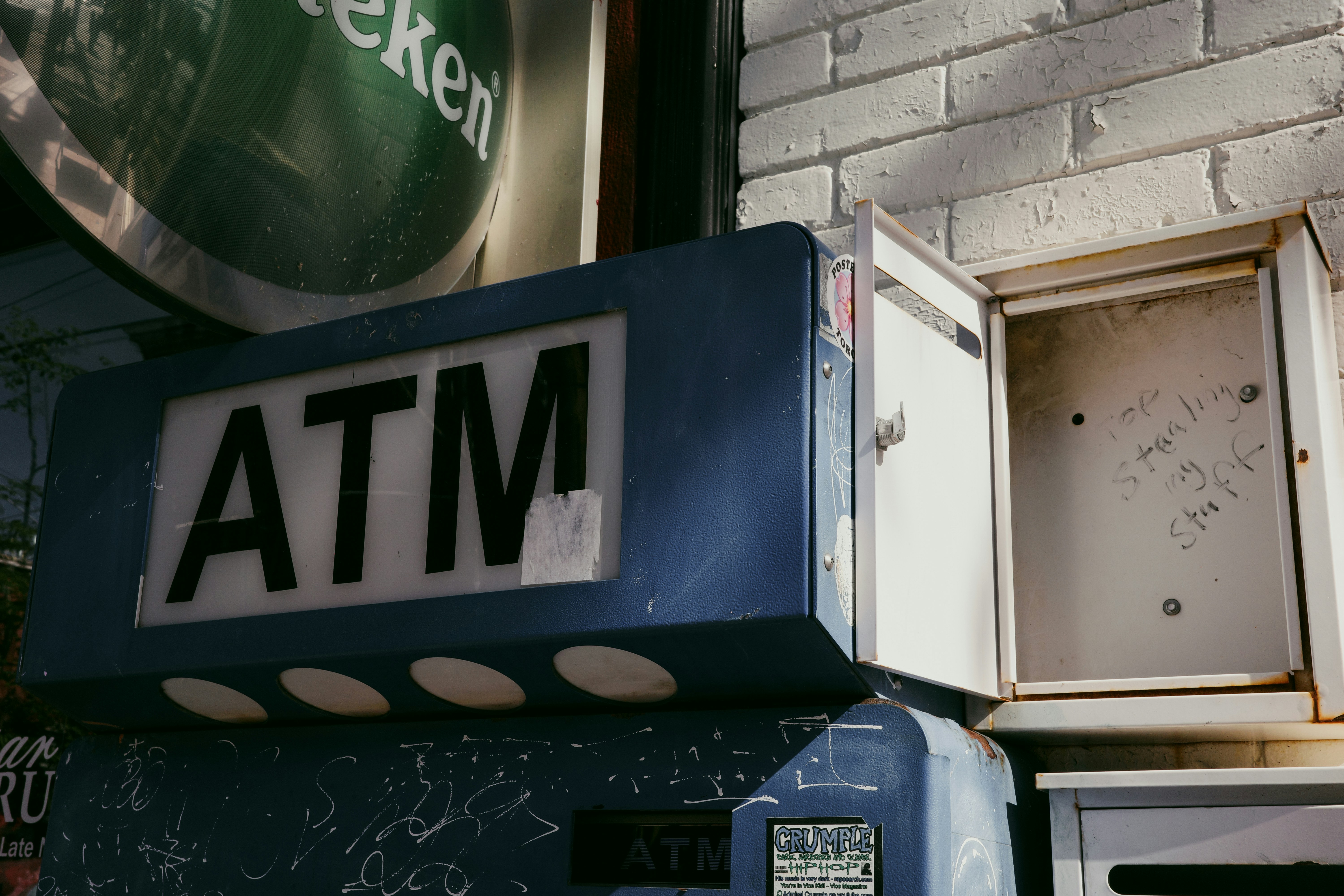 Blue ATM Enclosure Under Graffitied Wall