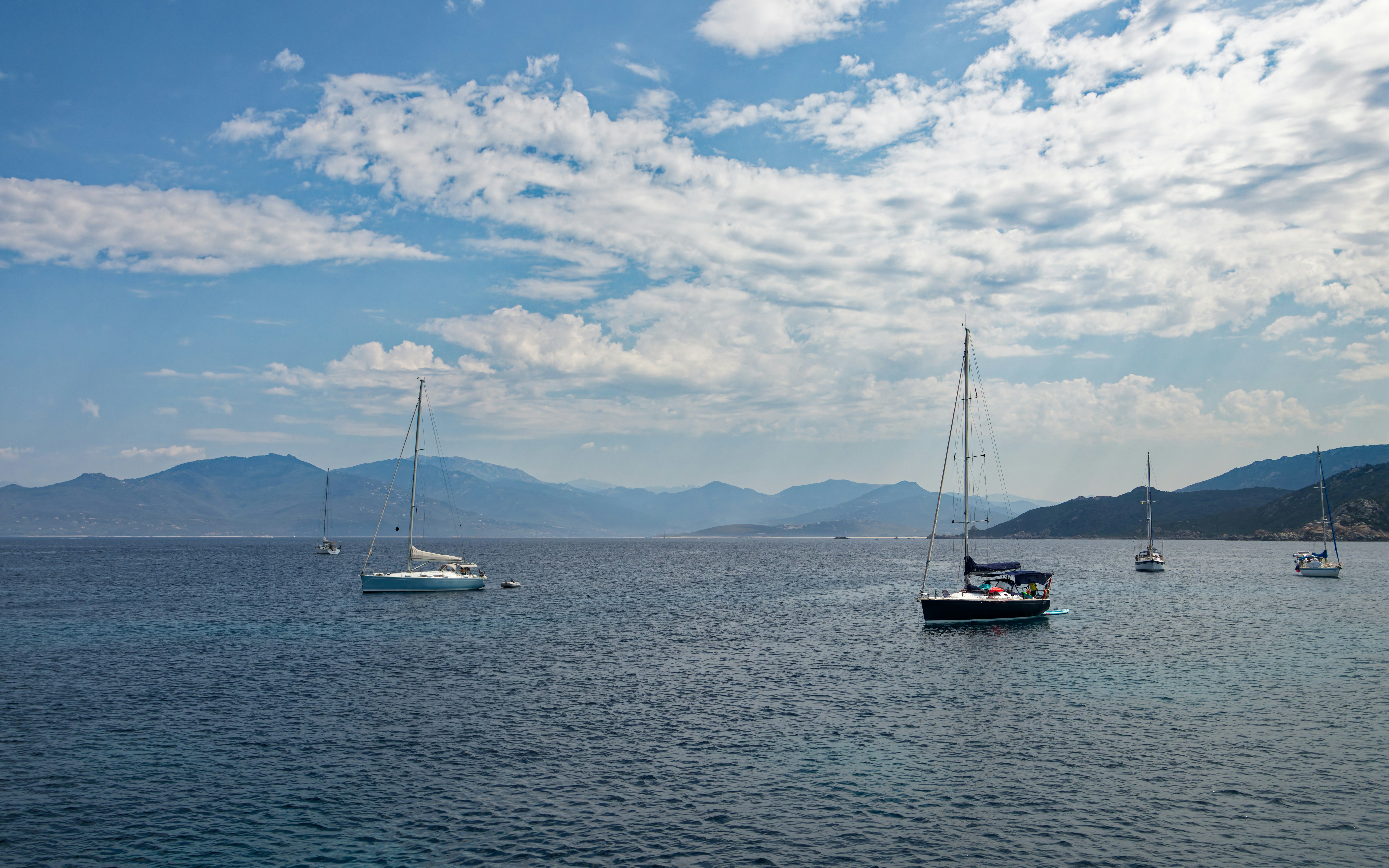 Sailboats Draped in Blue Calm Over a Distant Mountain Horizon