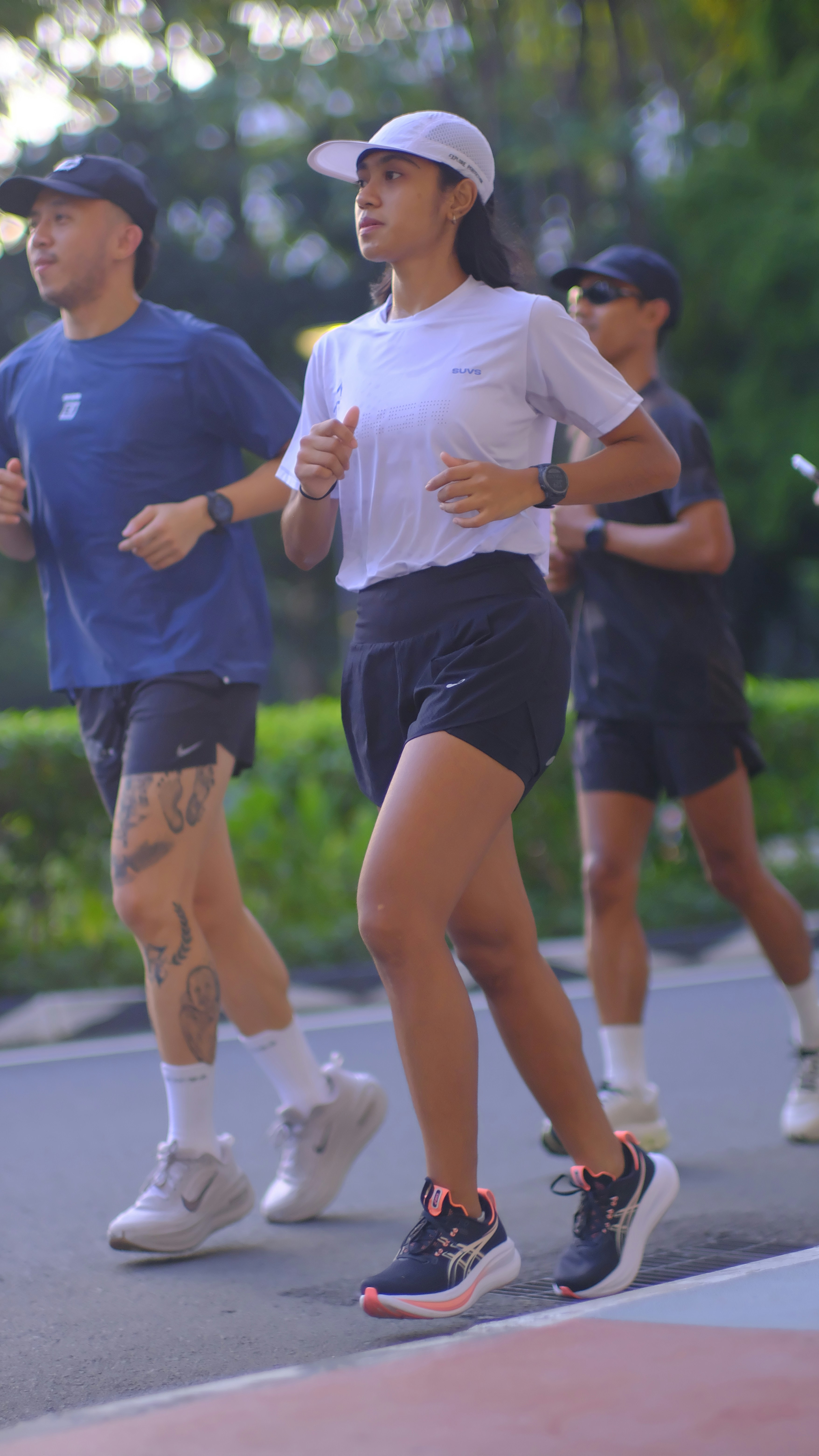 Focused stride: a trio of runners in motion on a sunlit park path