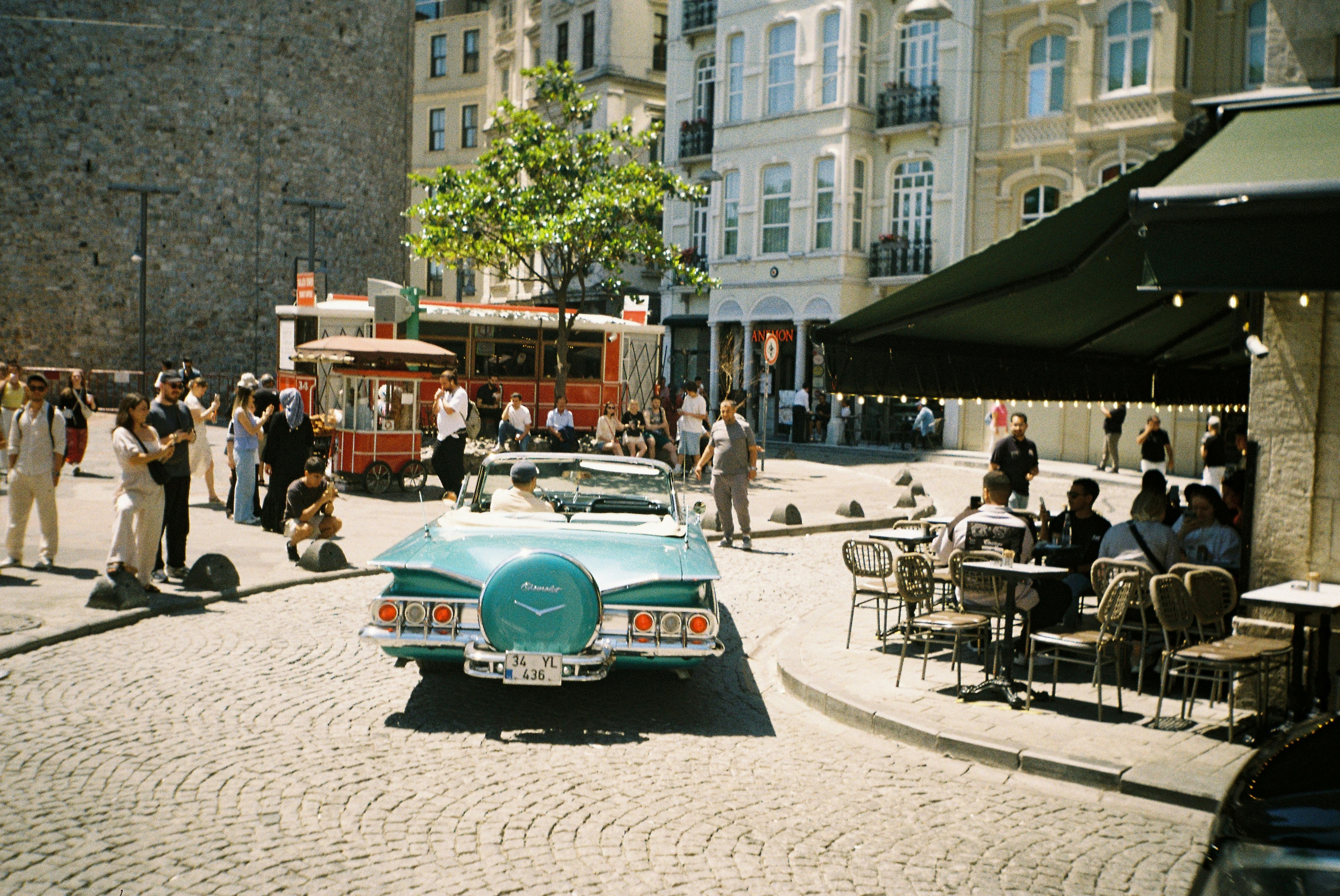 Cobblestone street scene with vintage car, cafe, and tram. photo – Free ...