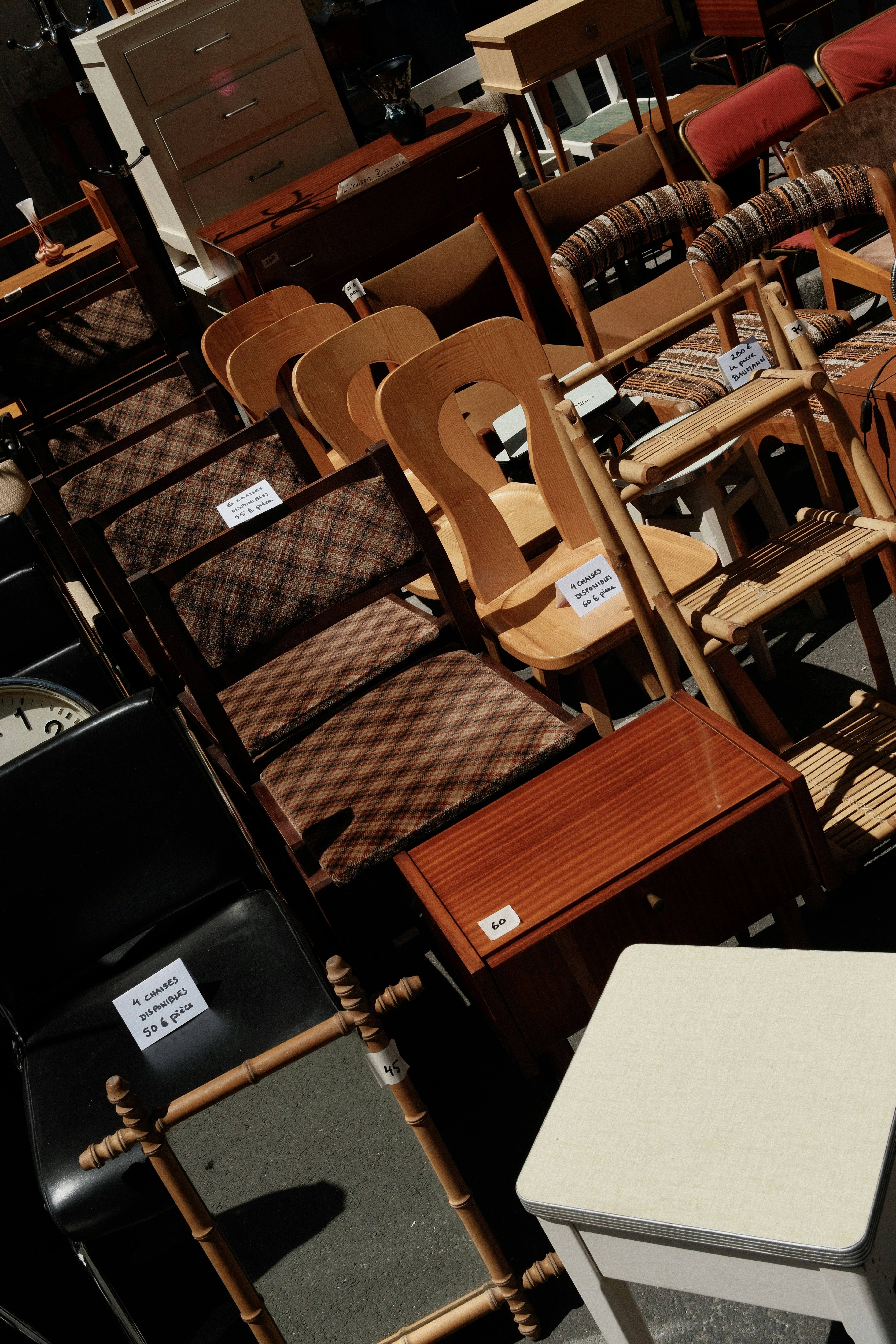 Auction Wardrobe: A Stack of Vintage Chairs and Tables in the Sunlit Lot