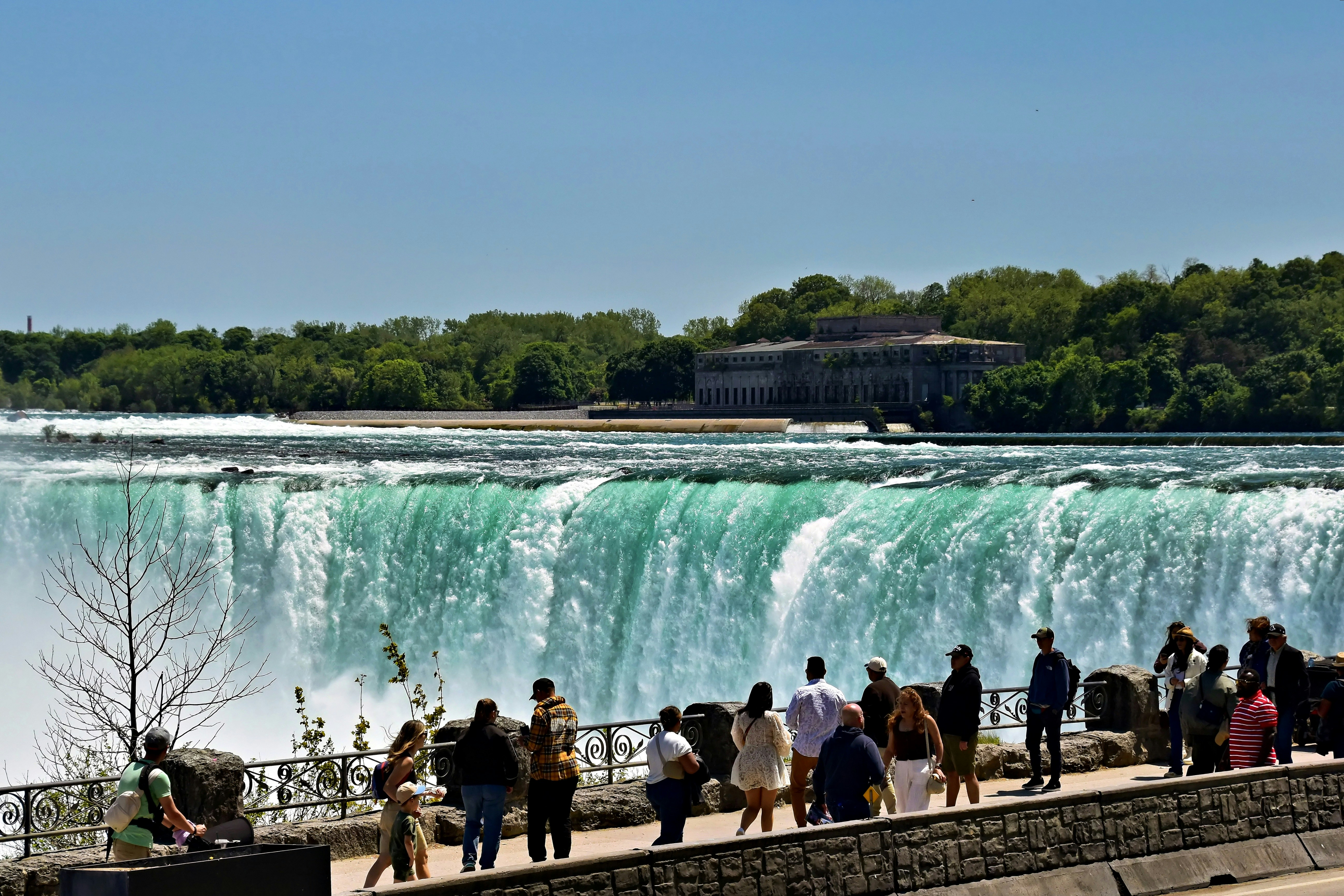 People overlook the verdant gorge as a turquoise cascade crashes over a wide ledge