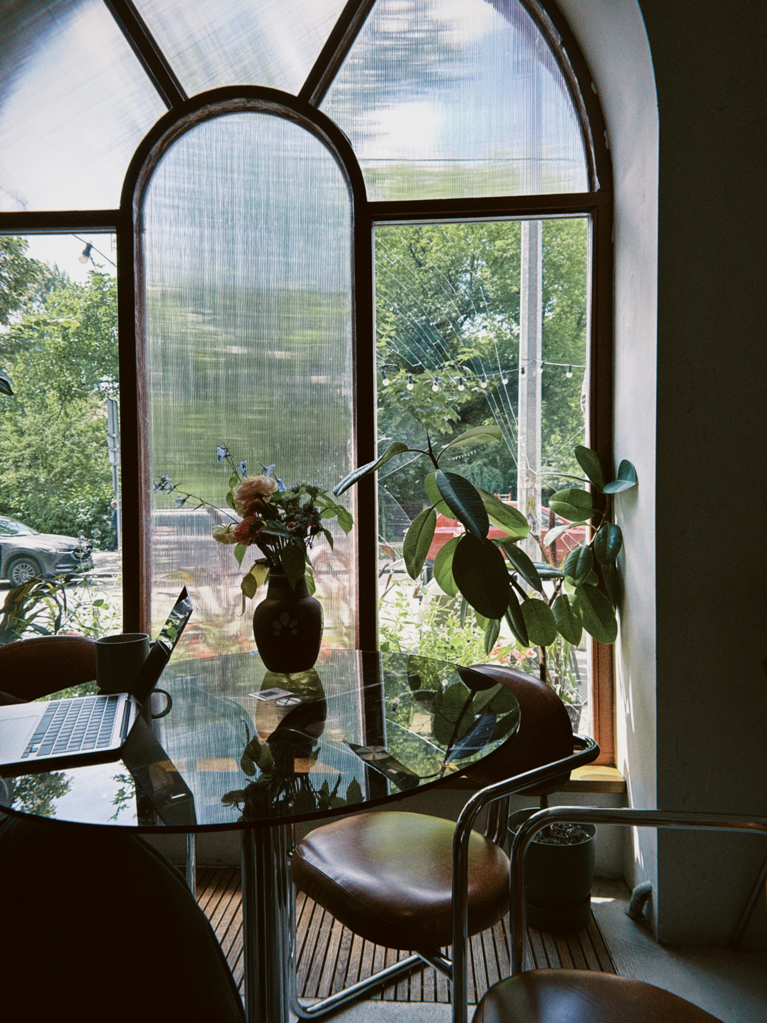 Sunlit Glass Table Reflections in a Verdant Conservatory