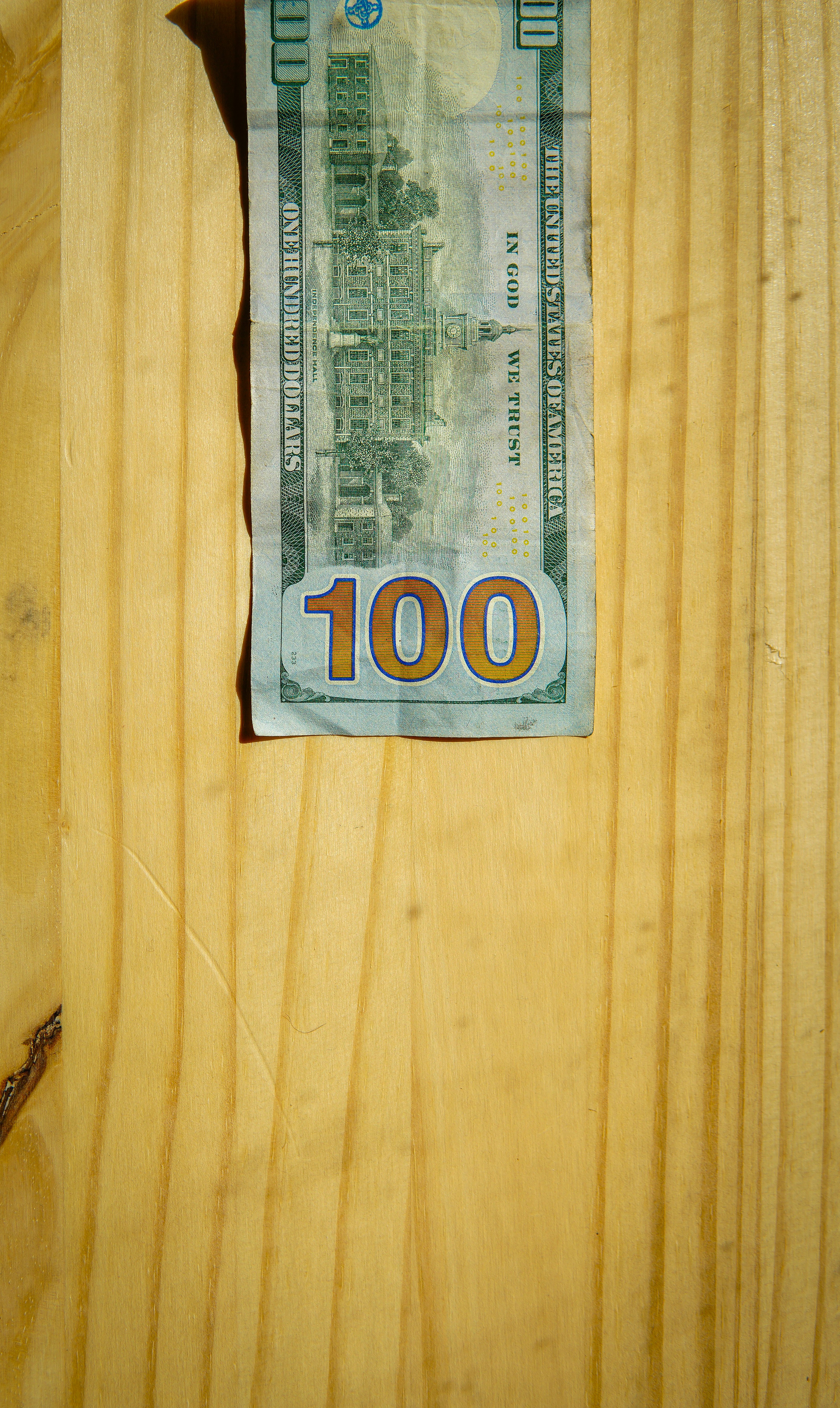 A Crumpled $100 Tucked into a Wooden Slit