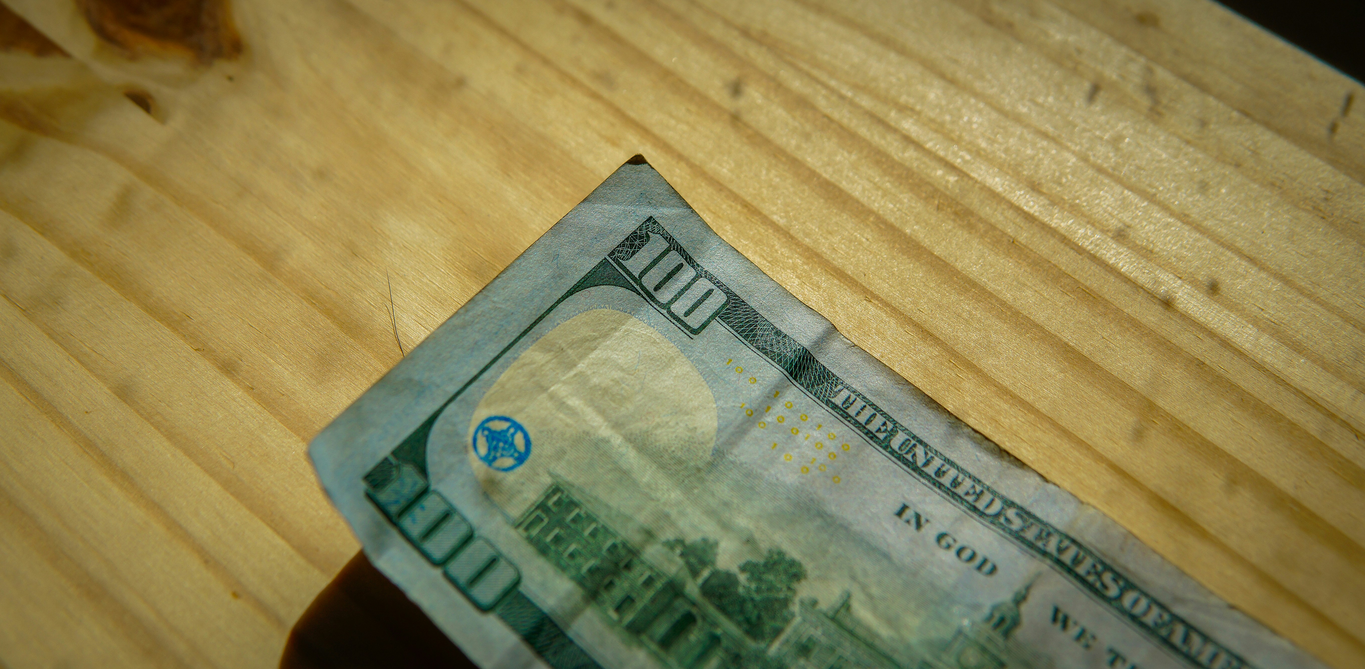 Cash Fold: A Dollar Gripped on a Wooden Desk