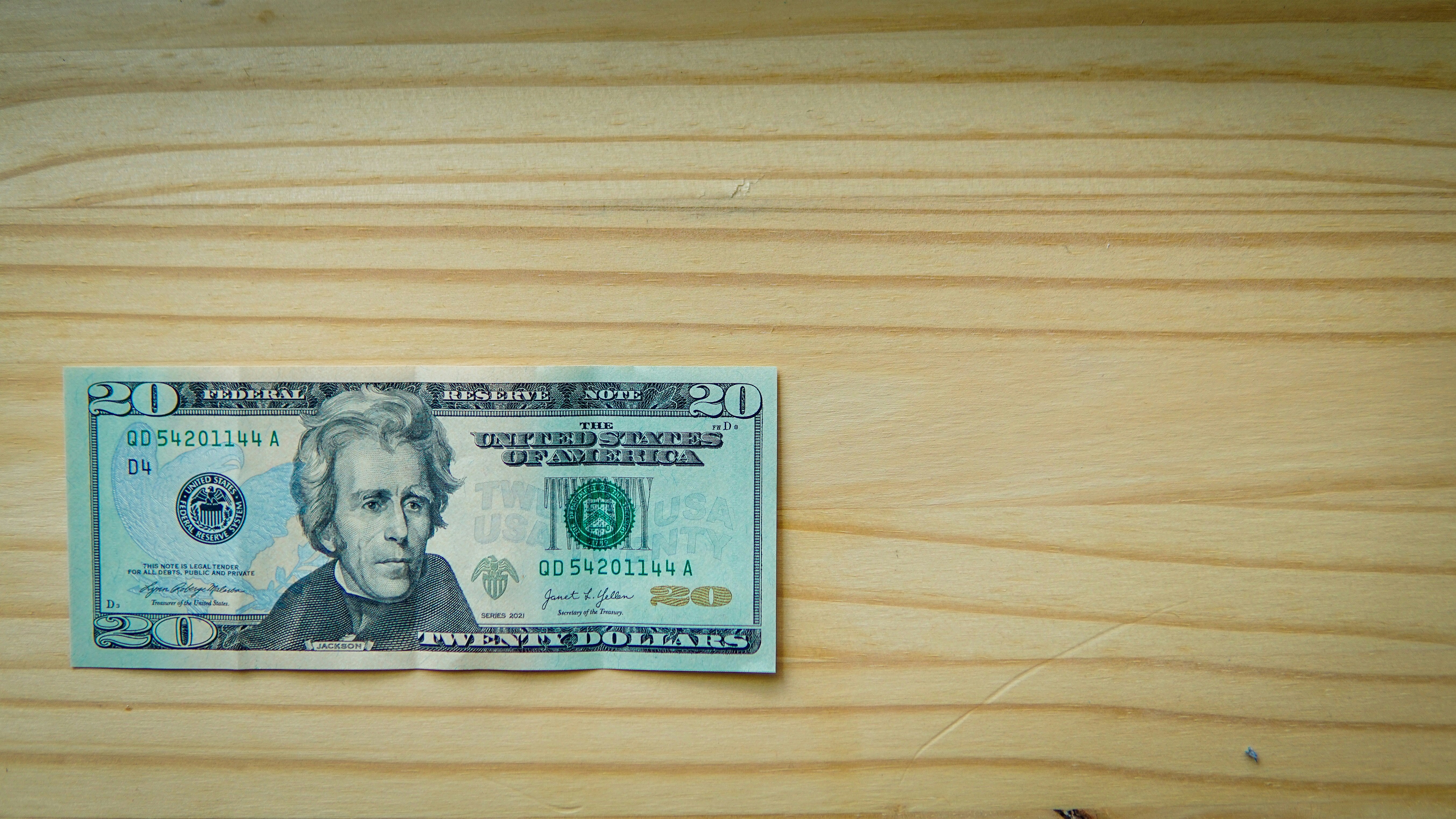 Folded Twenty: a blue bill resting on pale pine planks