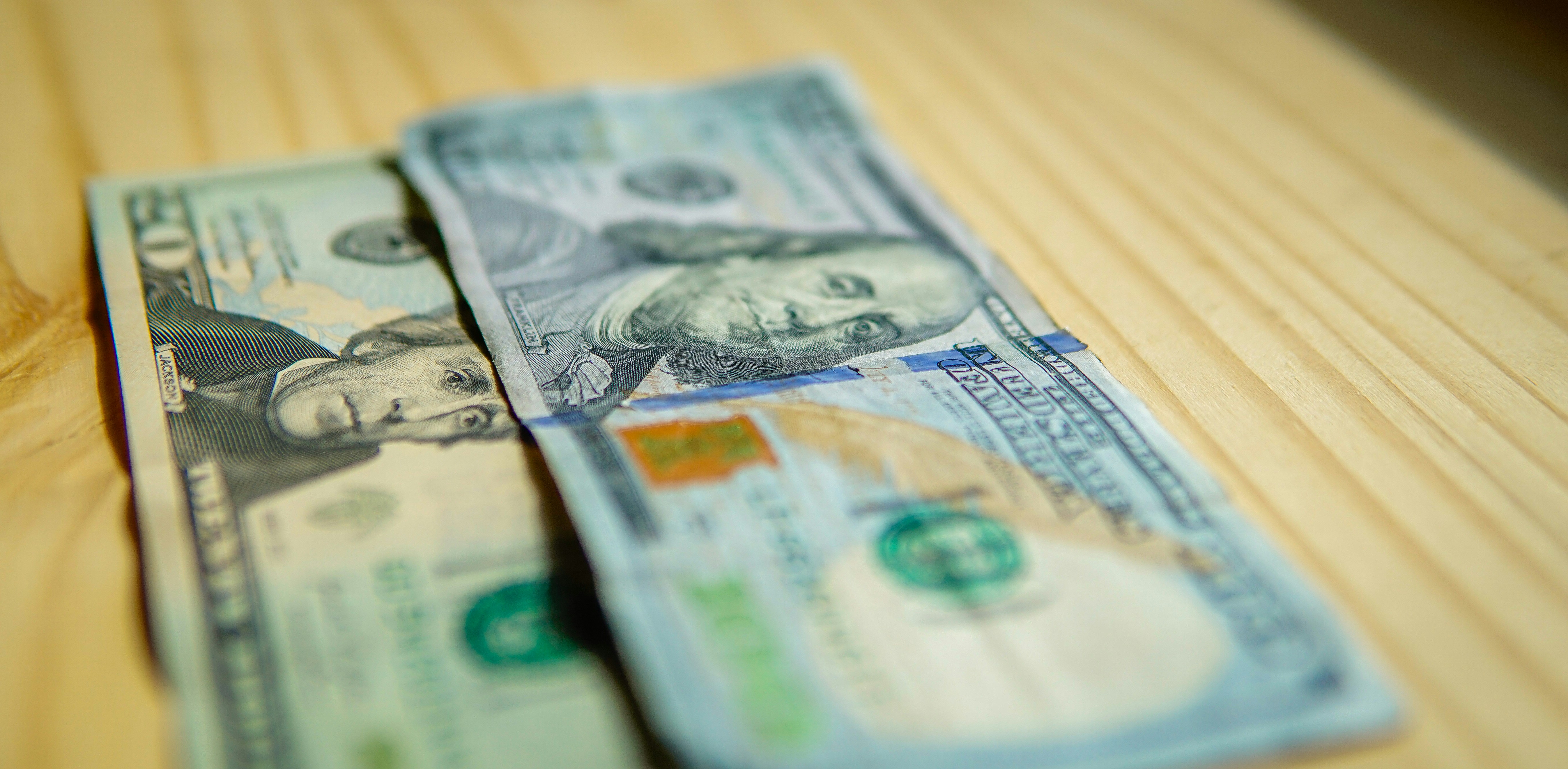 Folded currency on a wooden surface: a study in texture and hue